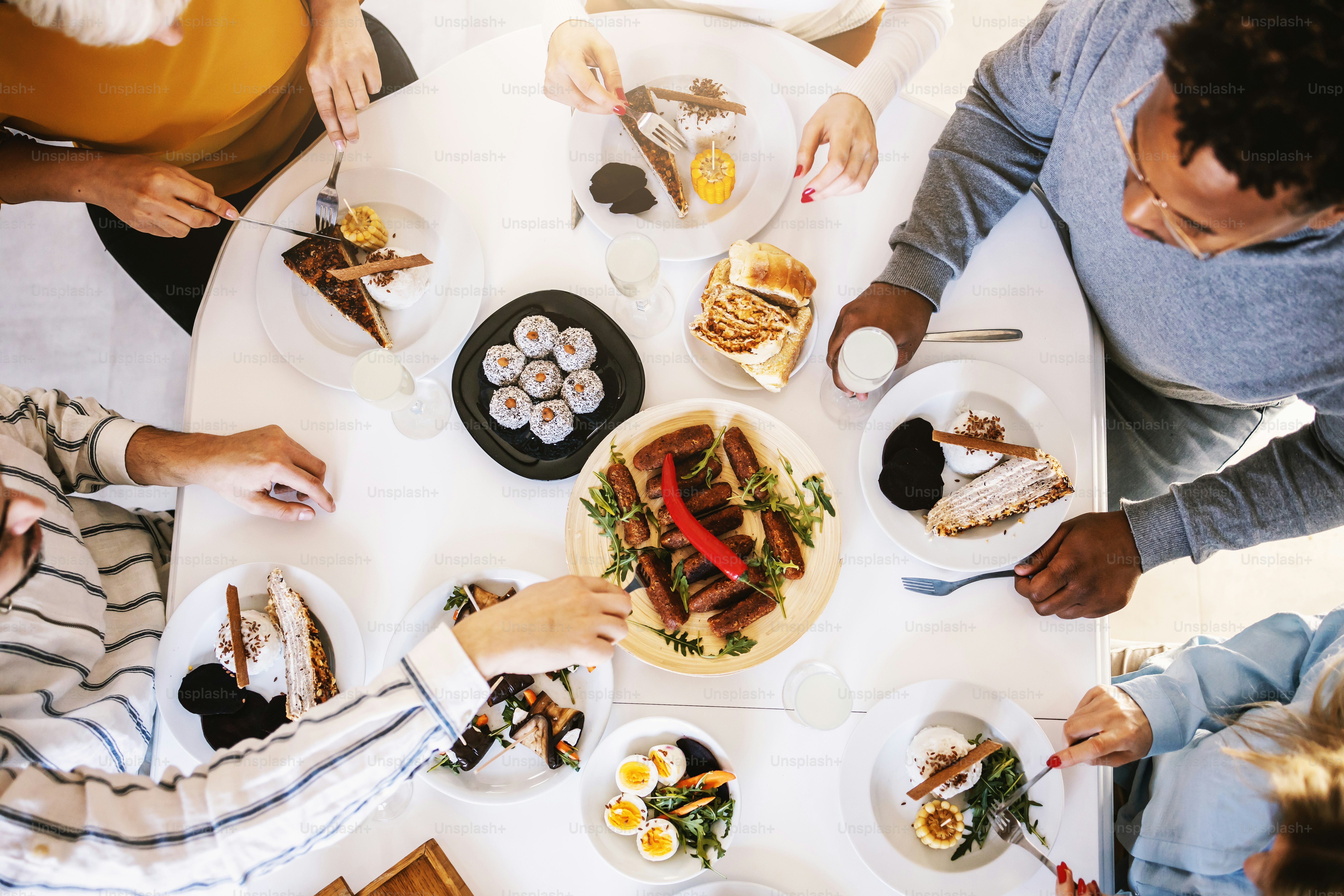 Top view of five multicultural friends sitting at dinning table and ...