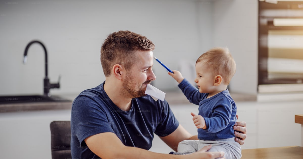 Jeune Père Barbu Séduisant Assis à Table à Manger Et Jouant Avec Son
