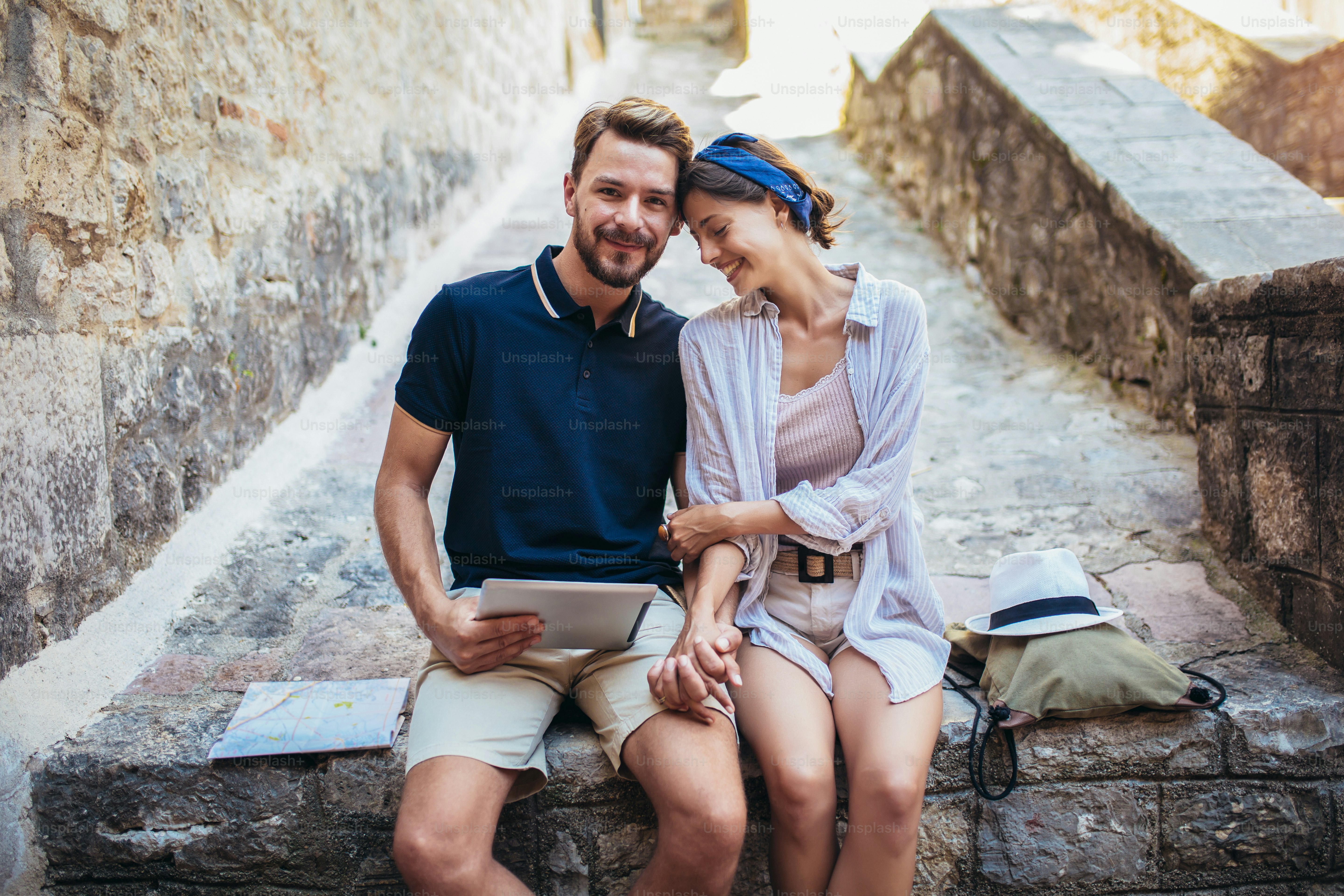 Romantic tourist couple sitting on stairs using digital tablet. photo ...