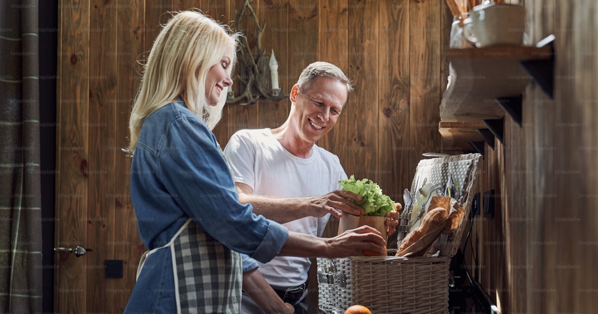 Foto Zum Thema Fröhlich Liebender Mann Und Frau Packen Obst Und Gemüse In Weidenkorb In Der