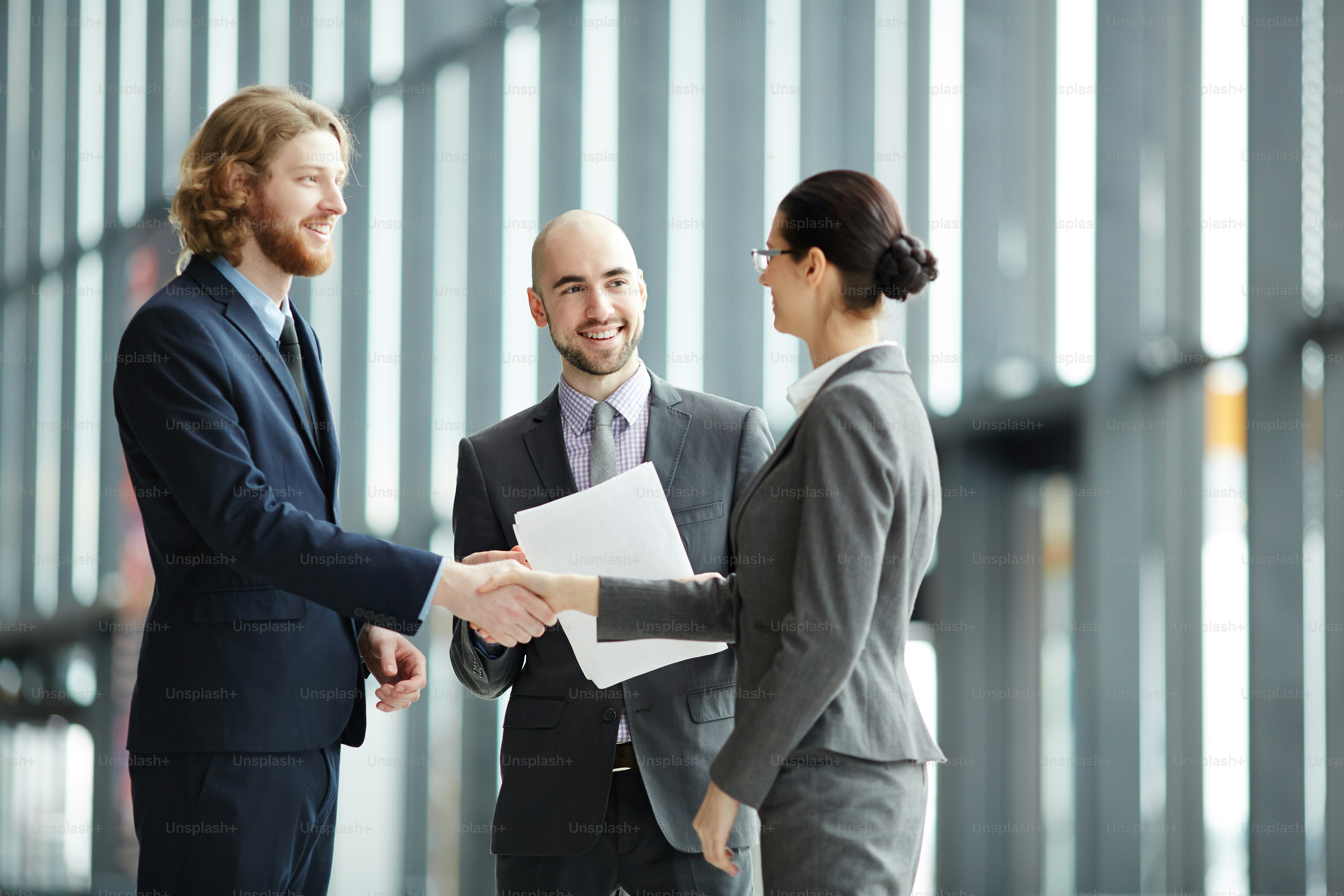 Two happy business partners greeting one another by handshake with ...