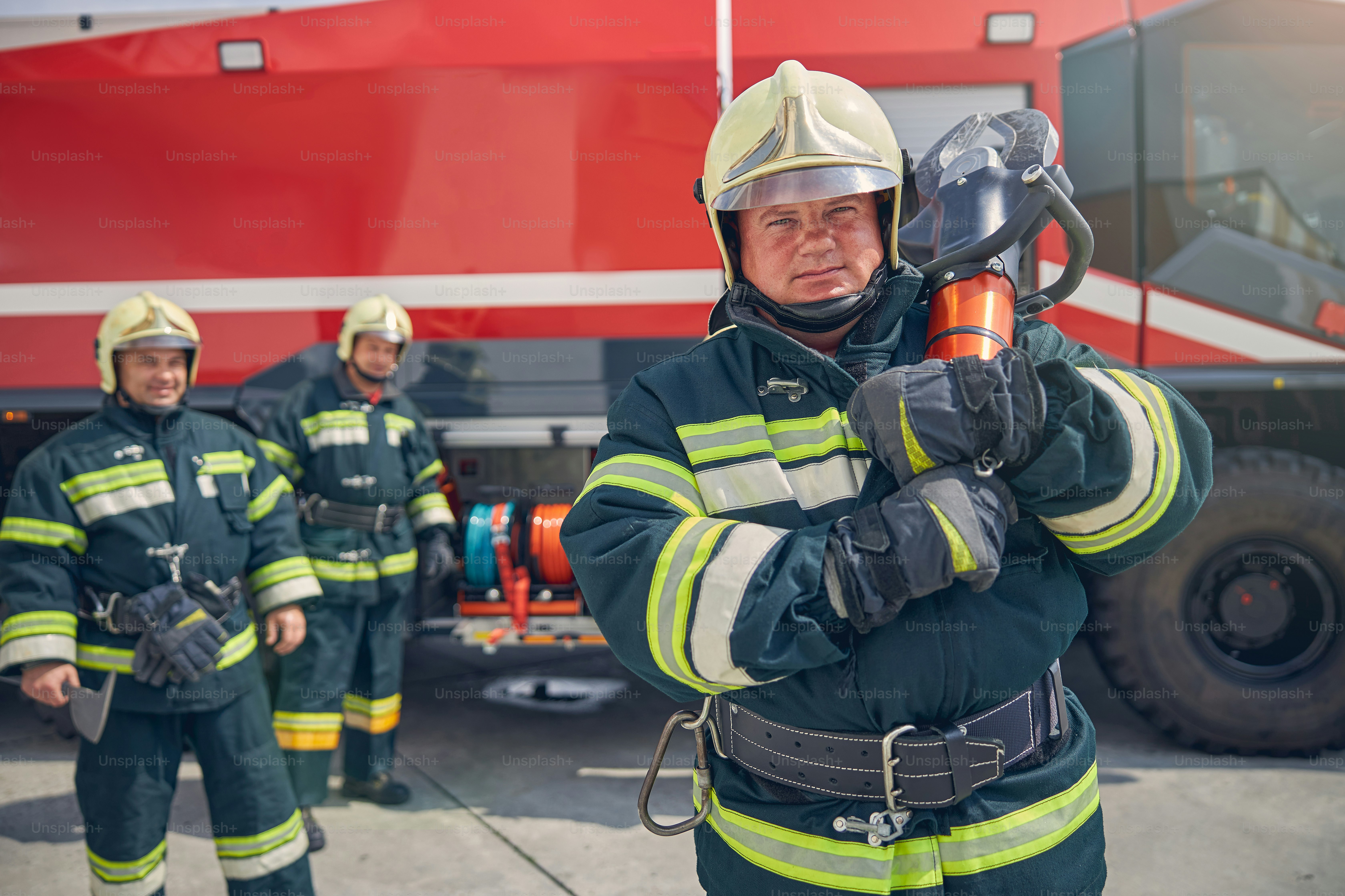 Mature strong firefighter posing at the photo camera with equipment in ...
