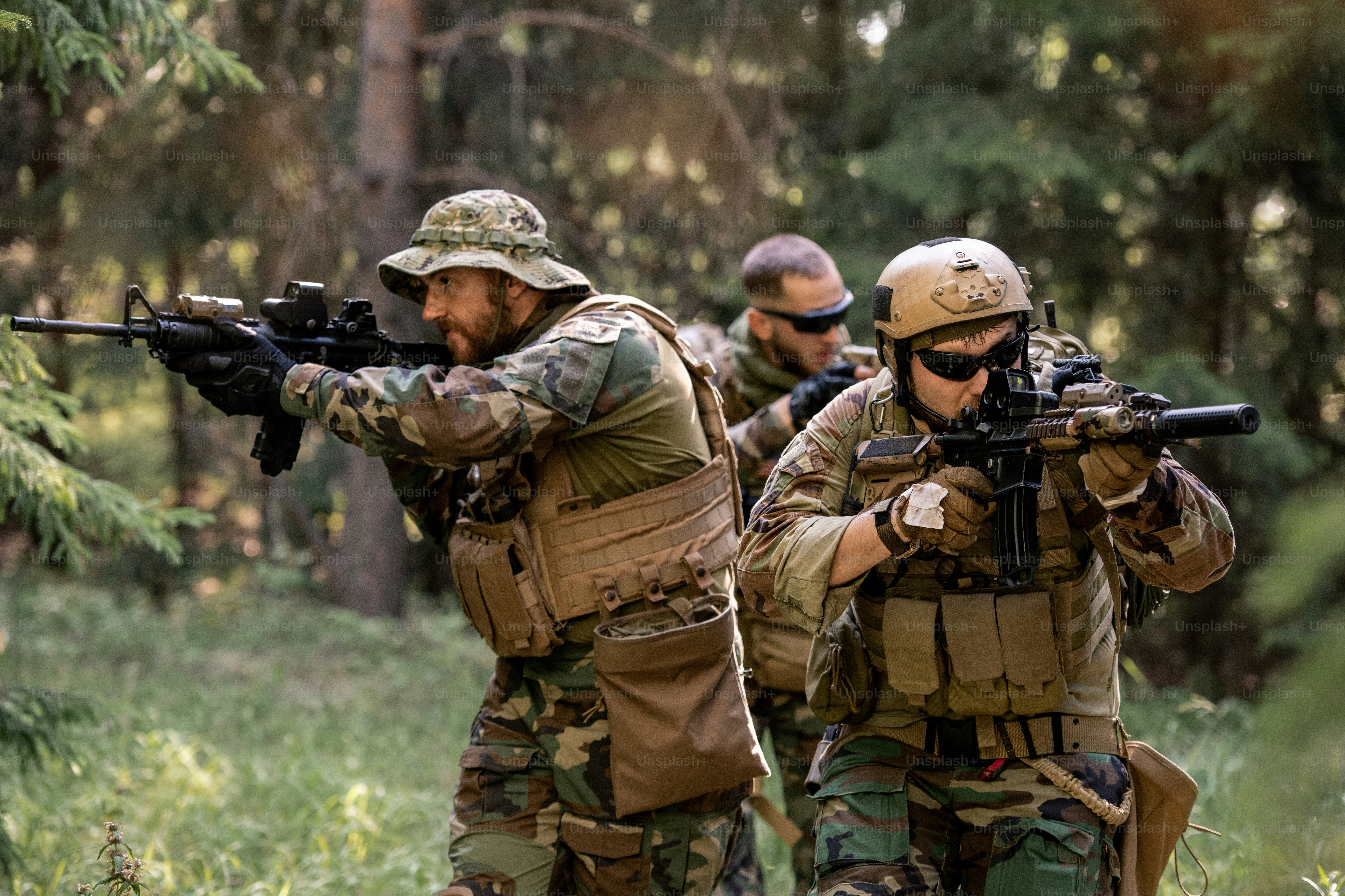 Group of attentive armed soldiers in camouflage outfits moving with ...