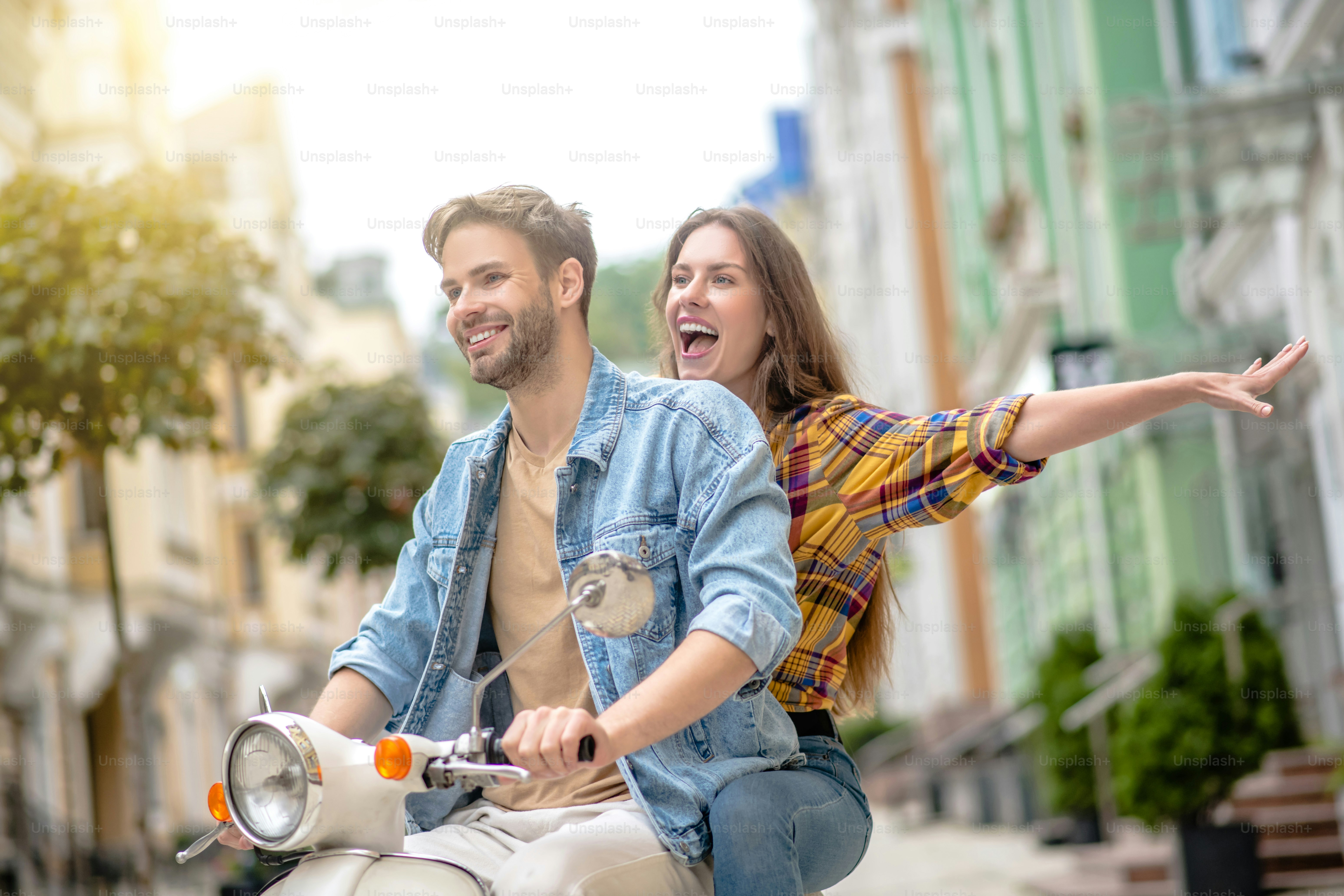 Pleasure to ride. A man and woman enjoying riding a scooter photo ...