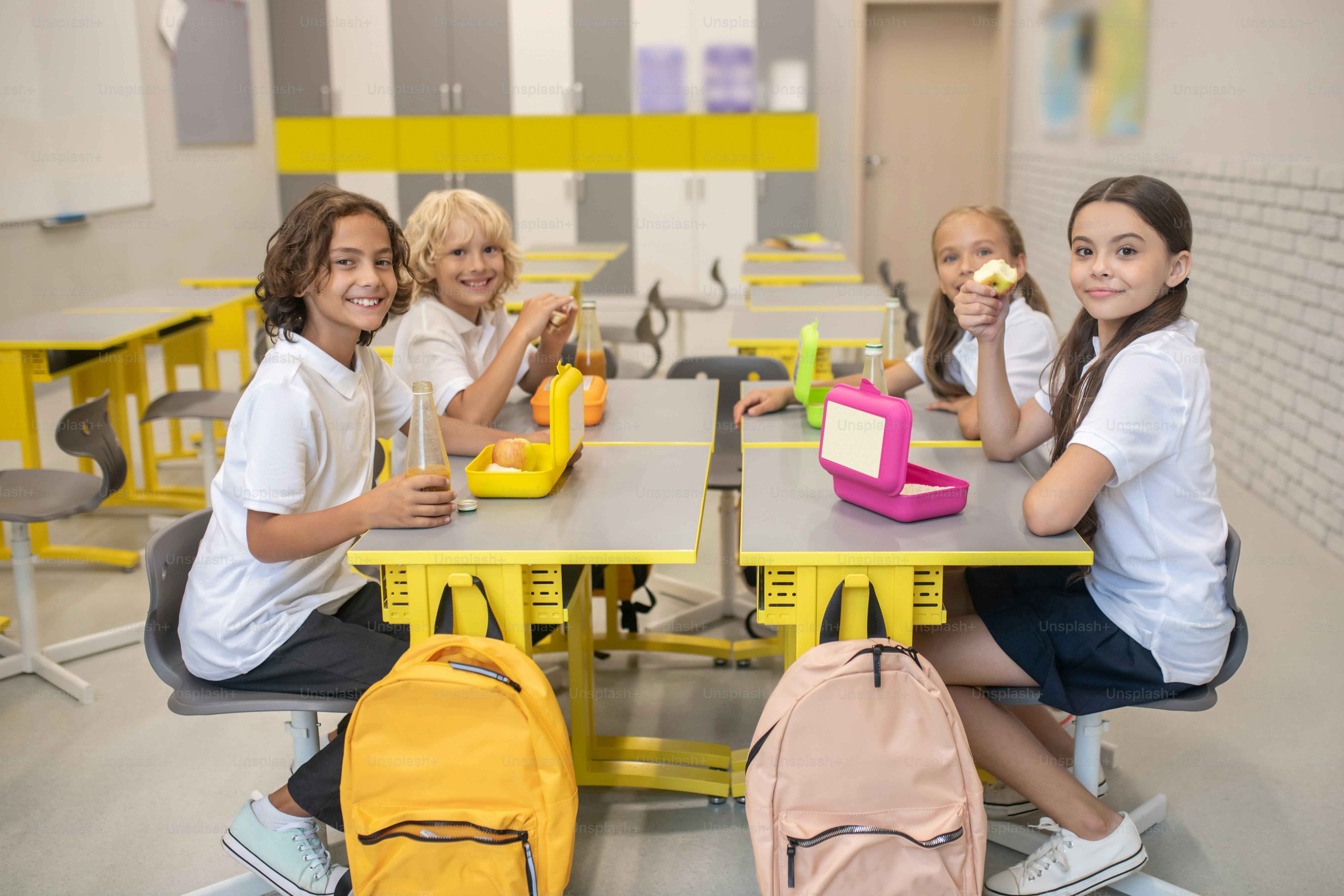 Lunch. Schoolchildren having lunch in the classrom and looking ...