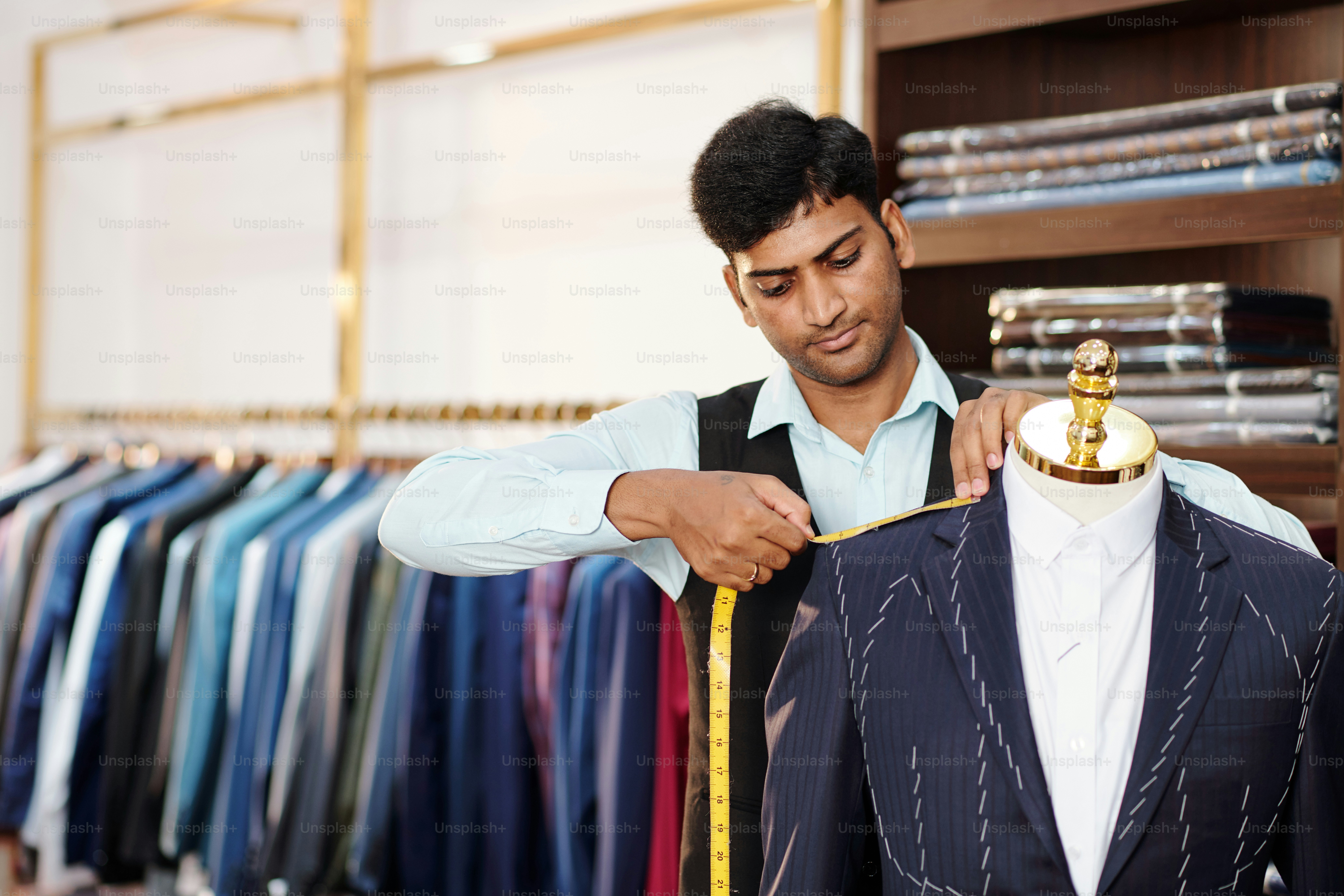 Serious Indian tailor taking measurements of bespoke suit jacket on ...