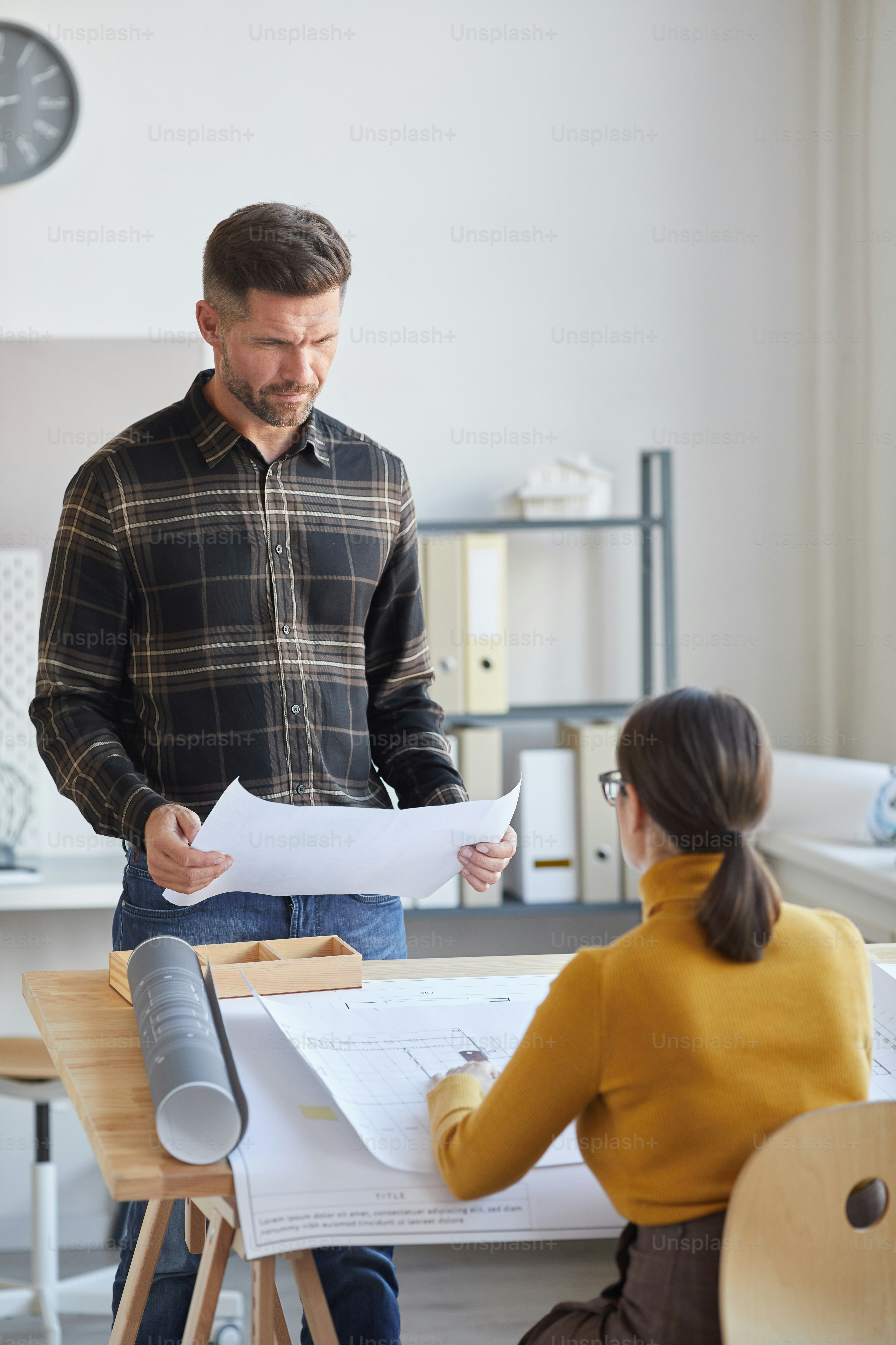 Vertical full length portrait of two architects holding blueprints and ...