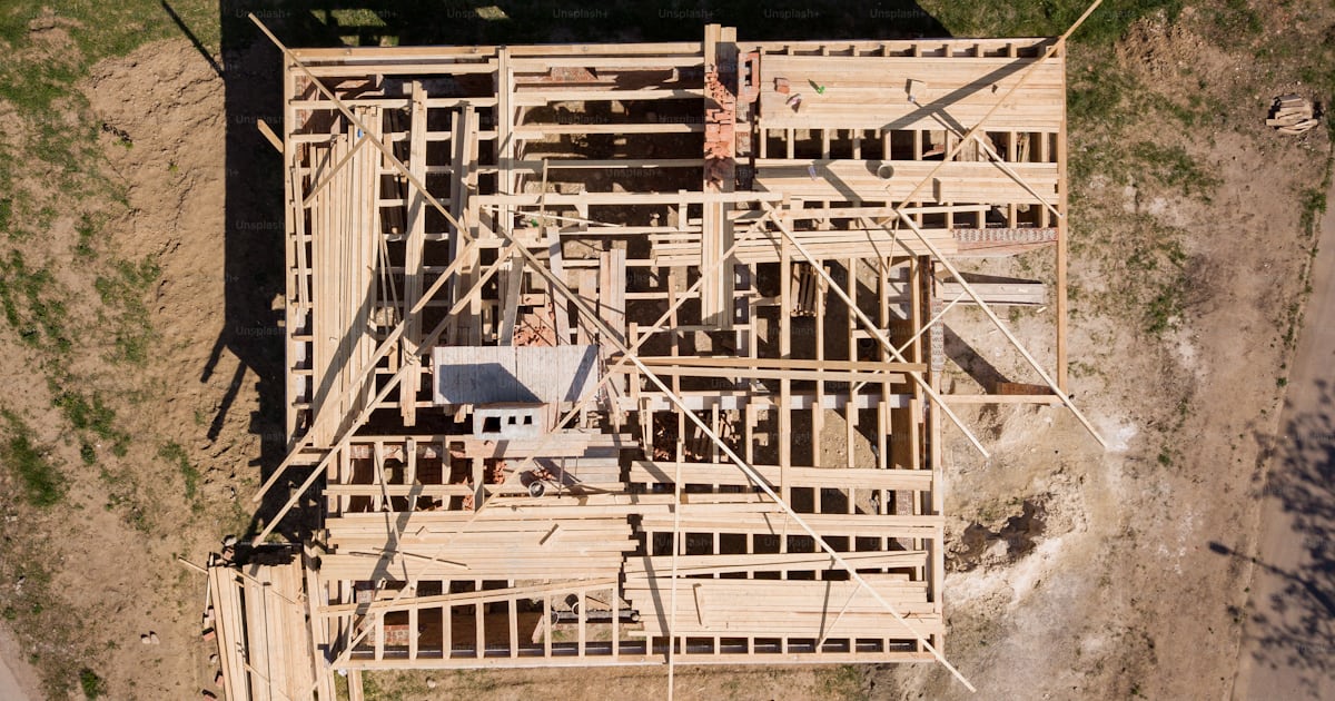 建設中の木製屋根フレーム構造を持つ未完成のレンガ造りの家の空撮。の写真 Unsplashの家の画像