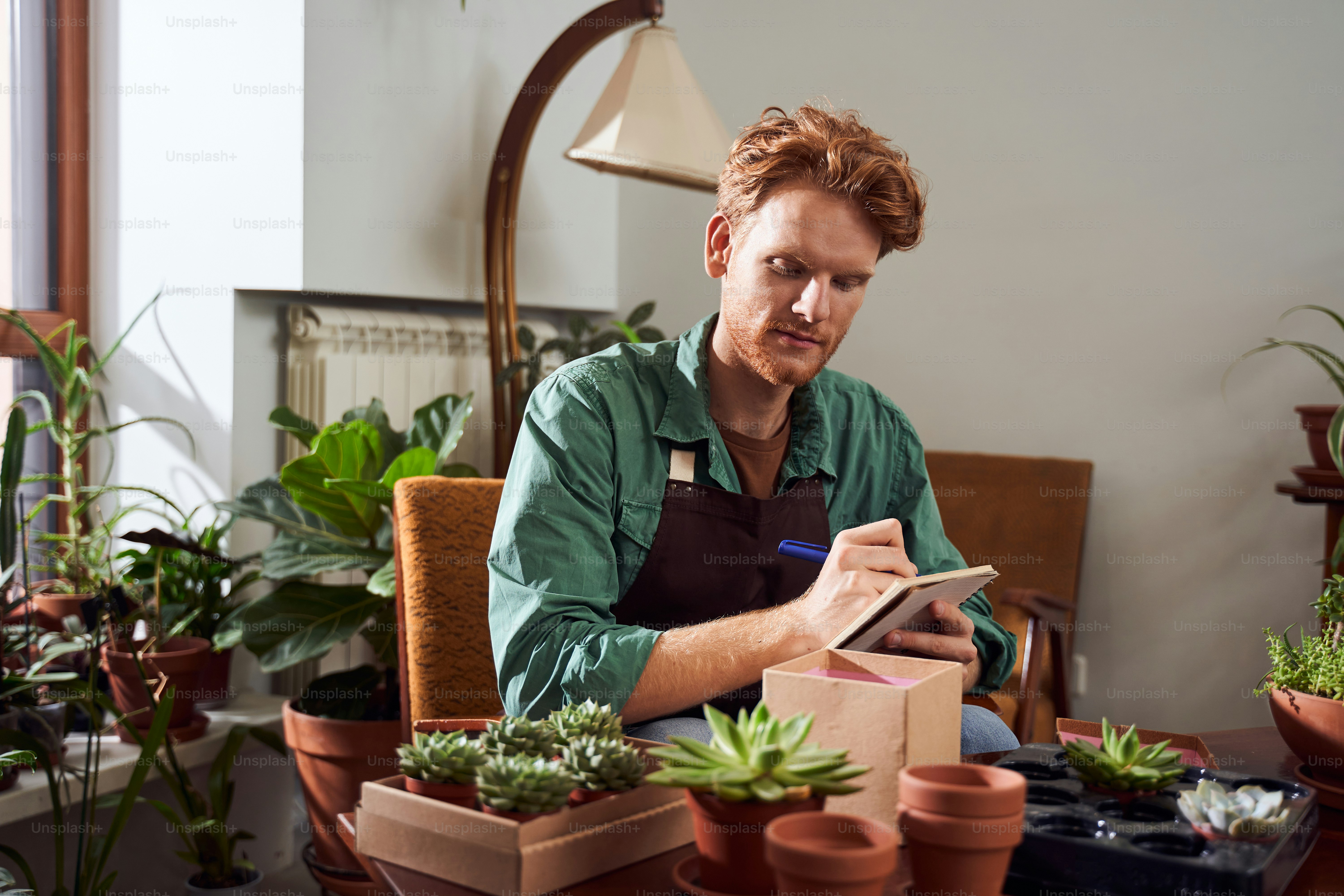 Portrait of red head florist writing notes in notebook in flower shop ...