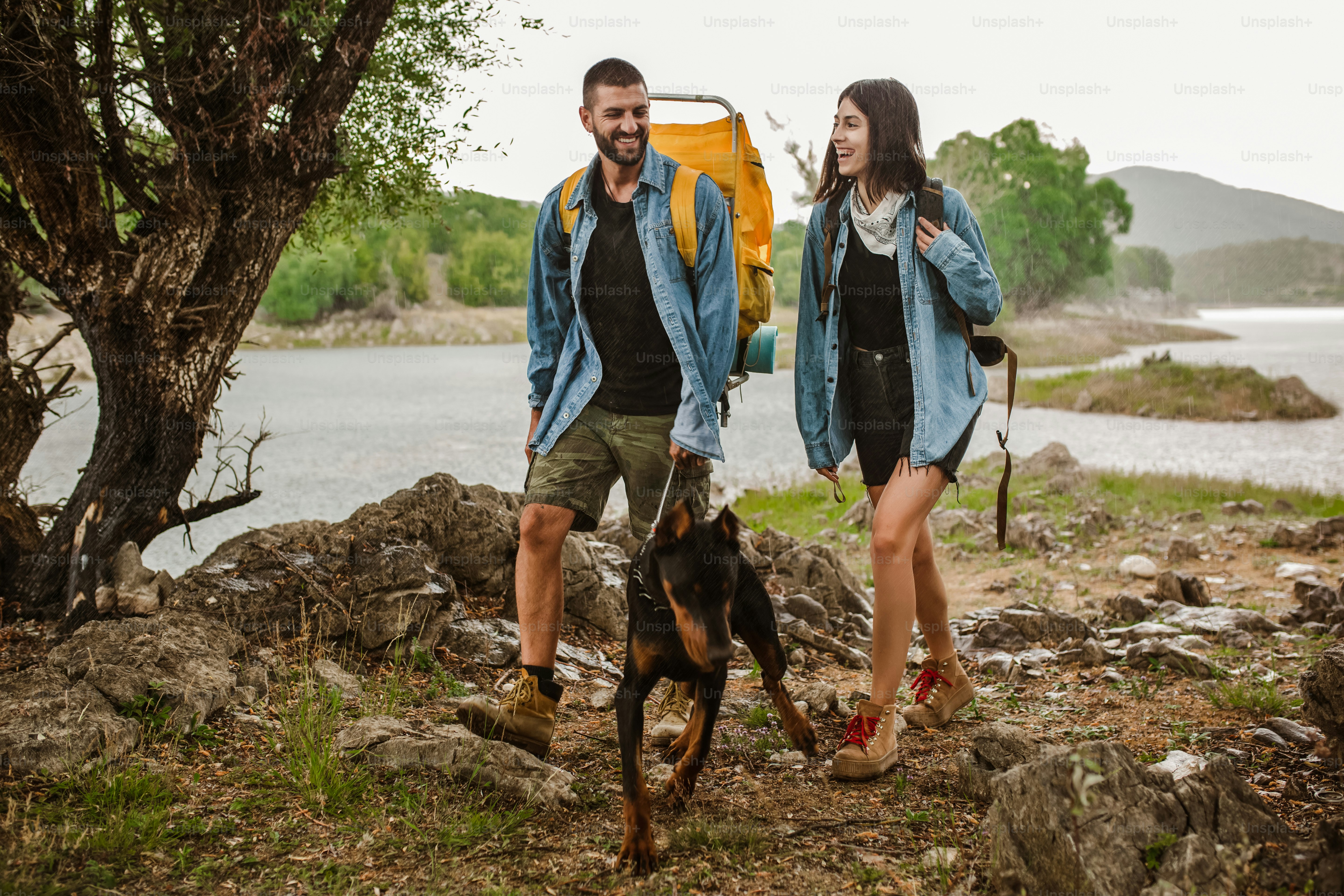 Foto Trek pareja de excursionistas y su perro caminando bajo la lluvia ...