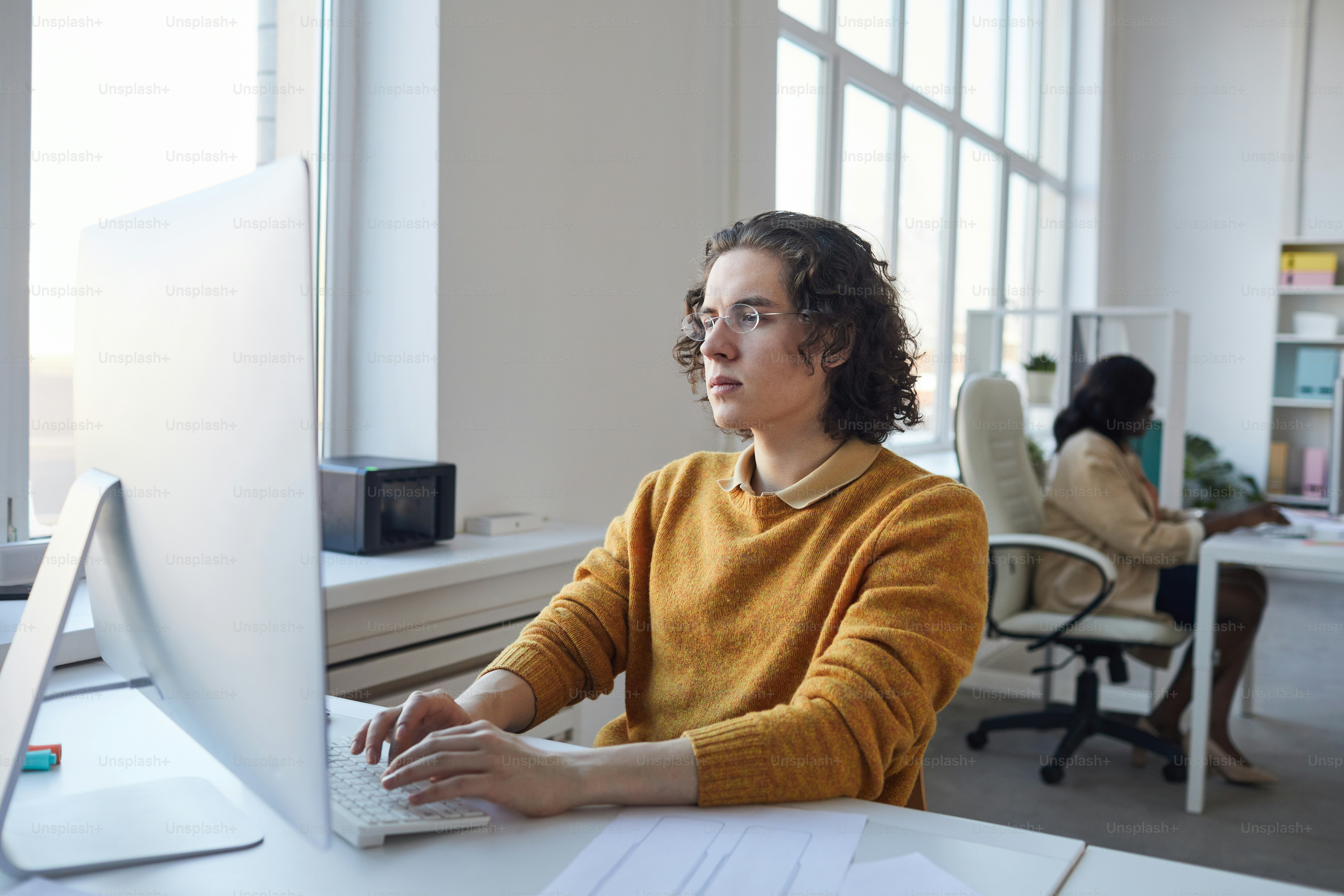 Side view portrait of young software developer using computer while ...