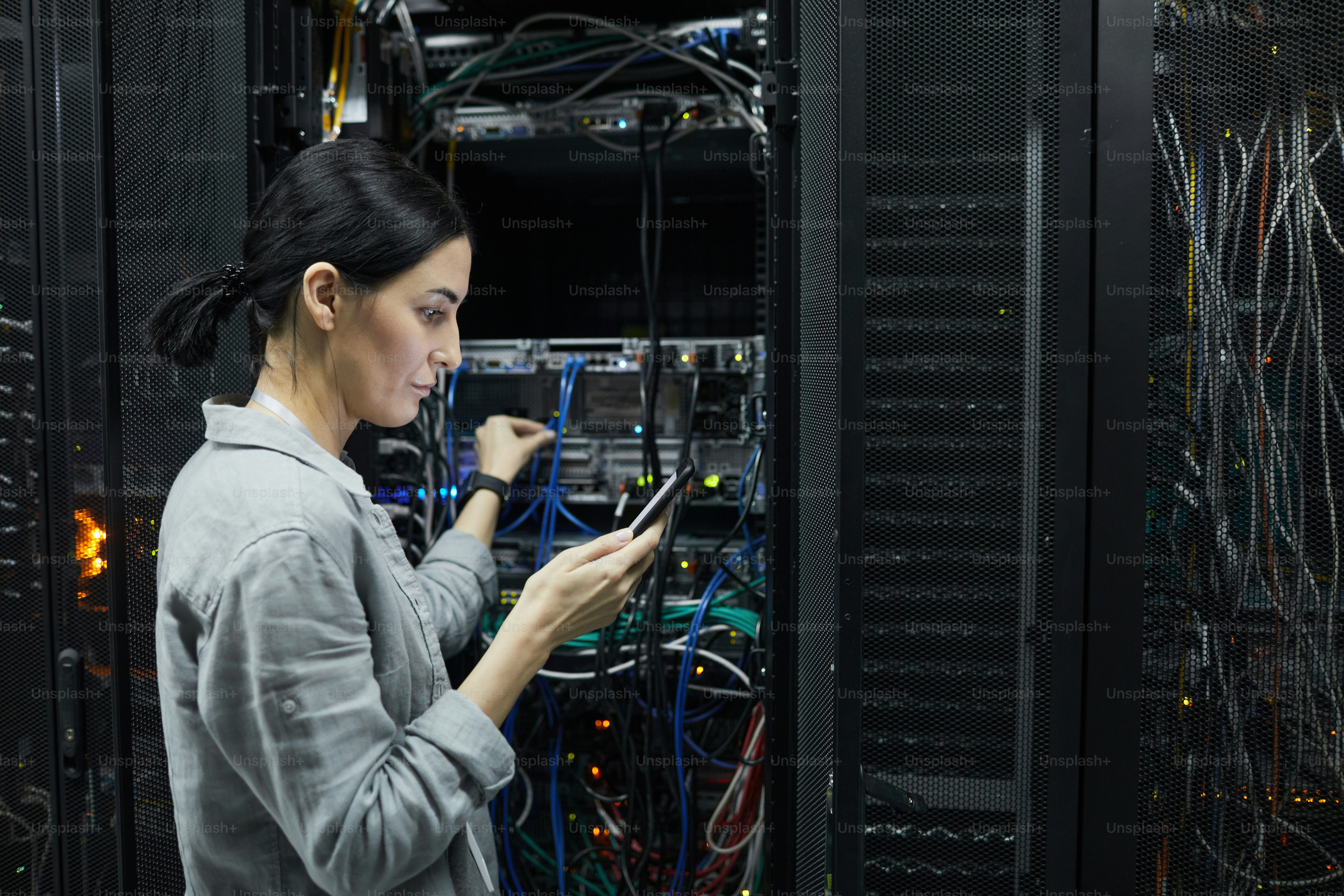 Close up of female network technician connecting cables in server ...