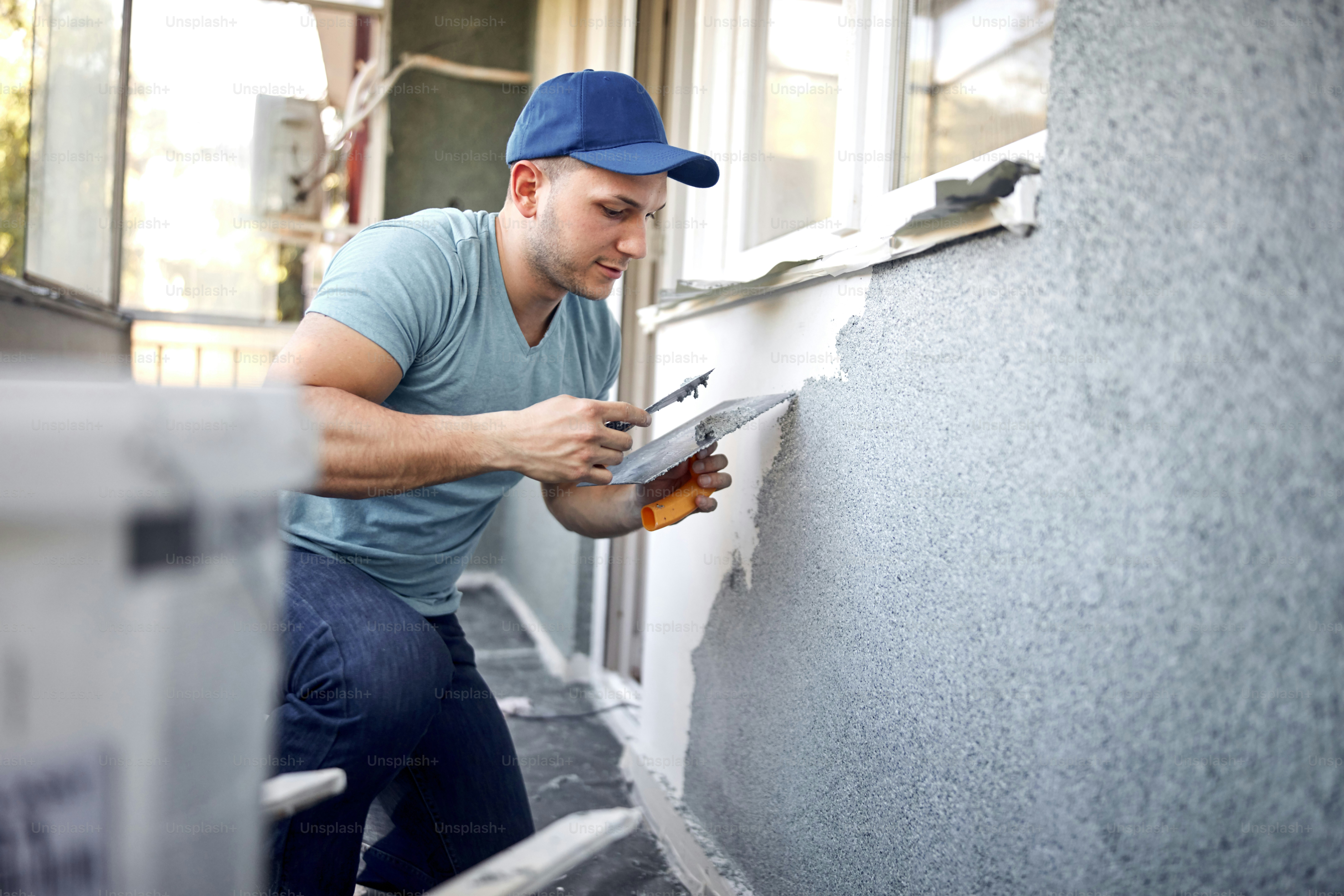 Man working on a house facade. photo – House Image on Unsplash