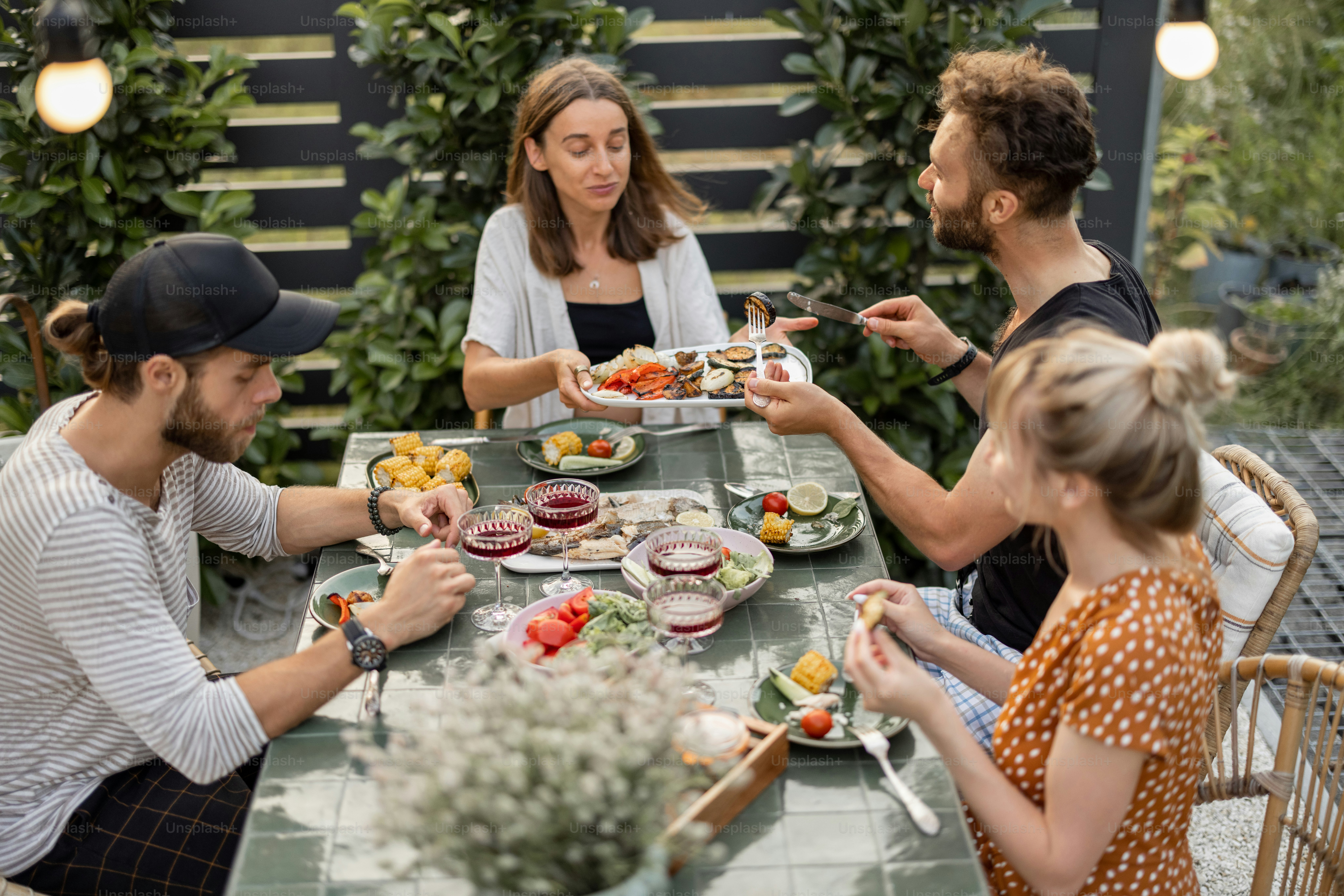 Small group of a young friends have a lunch outdoors, eating grilled ...