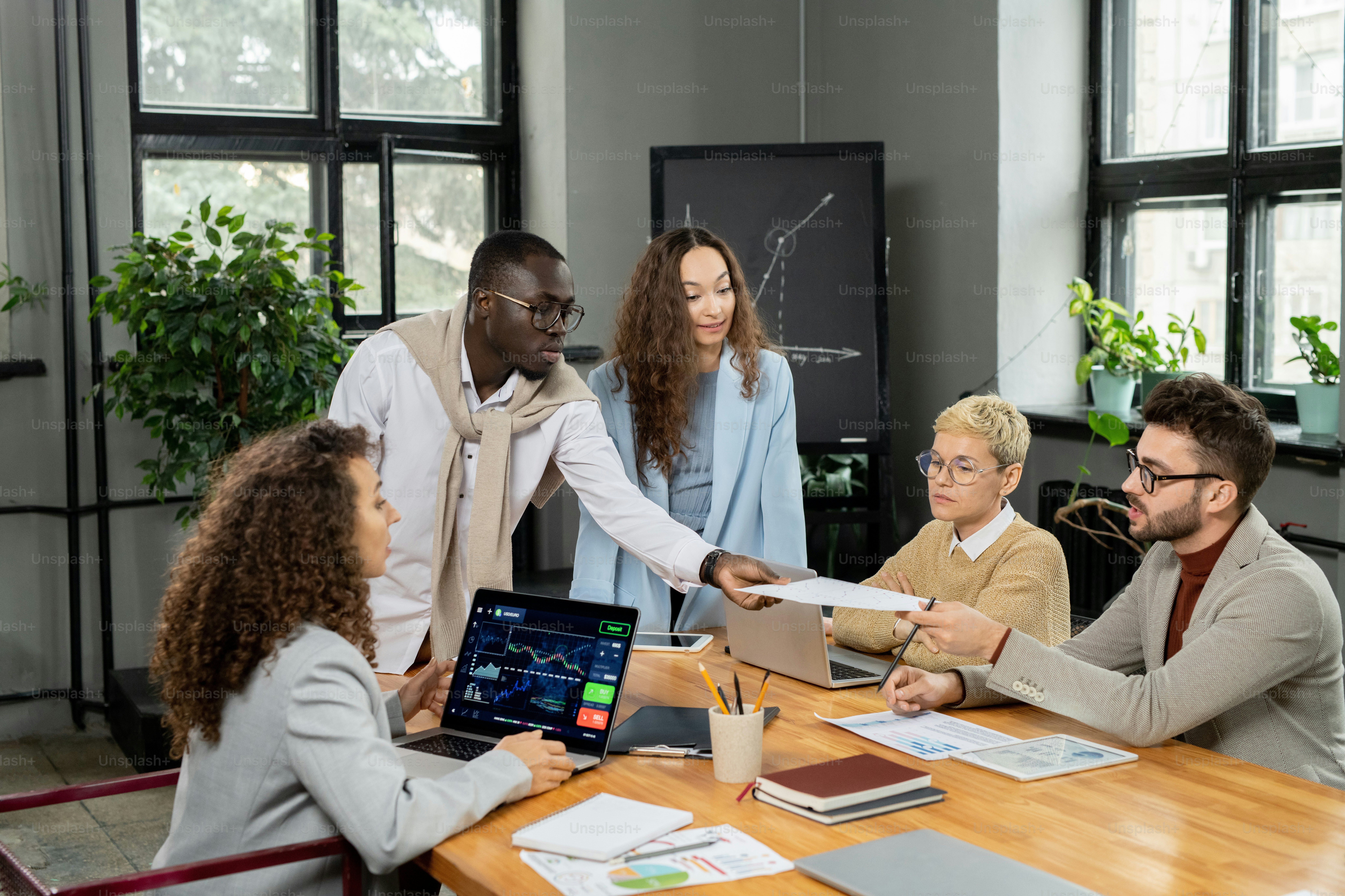 Young African businessman passing paper to one of colleagues photo ...