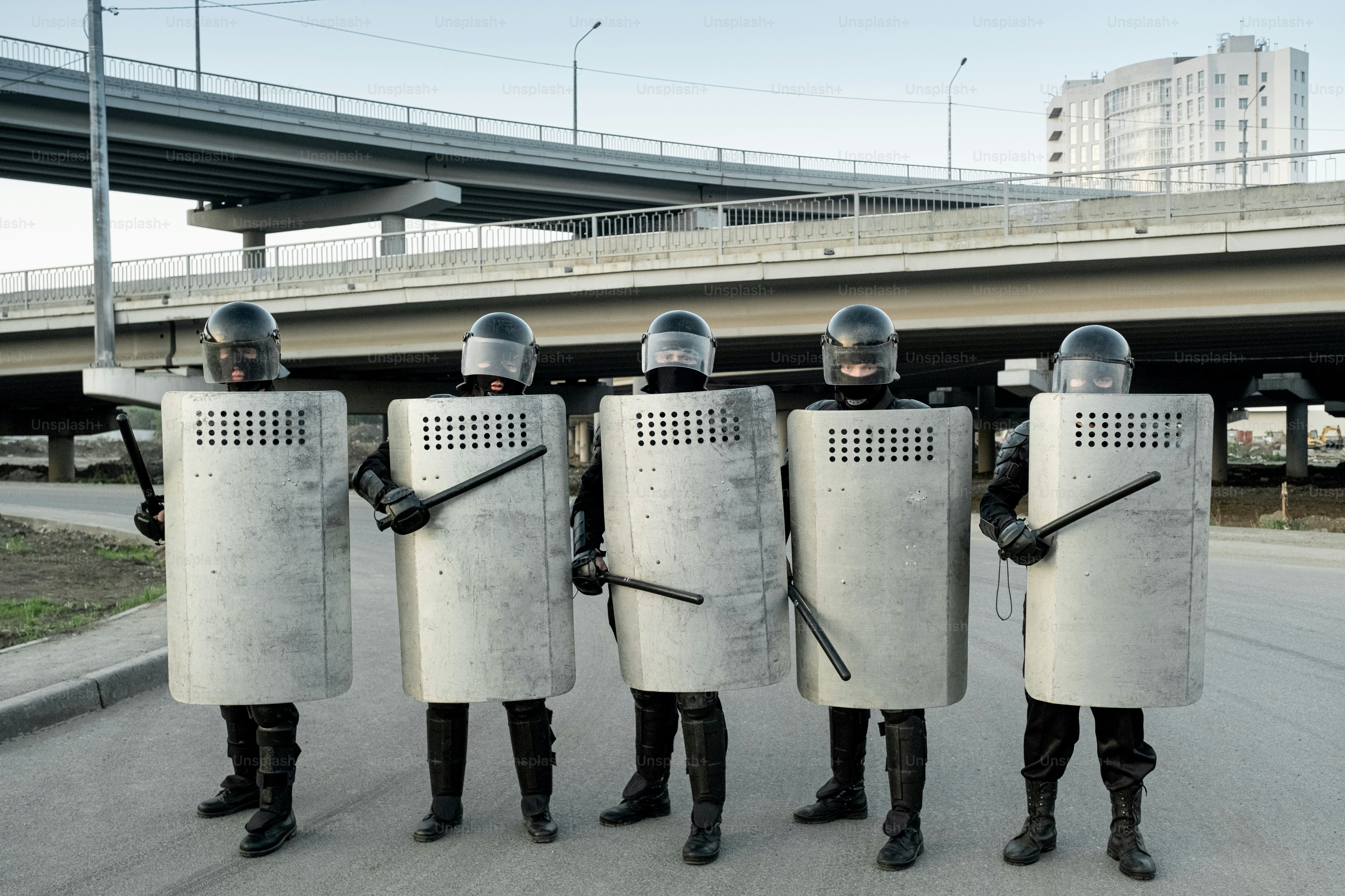 Group of police guards in uniform protected by shields standing with ...