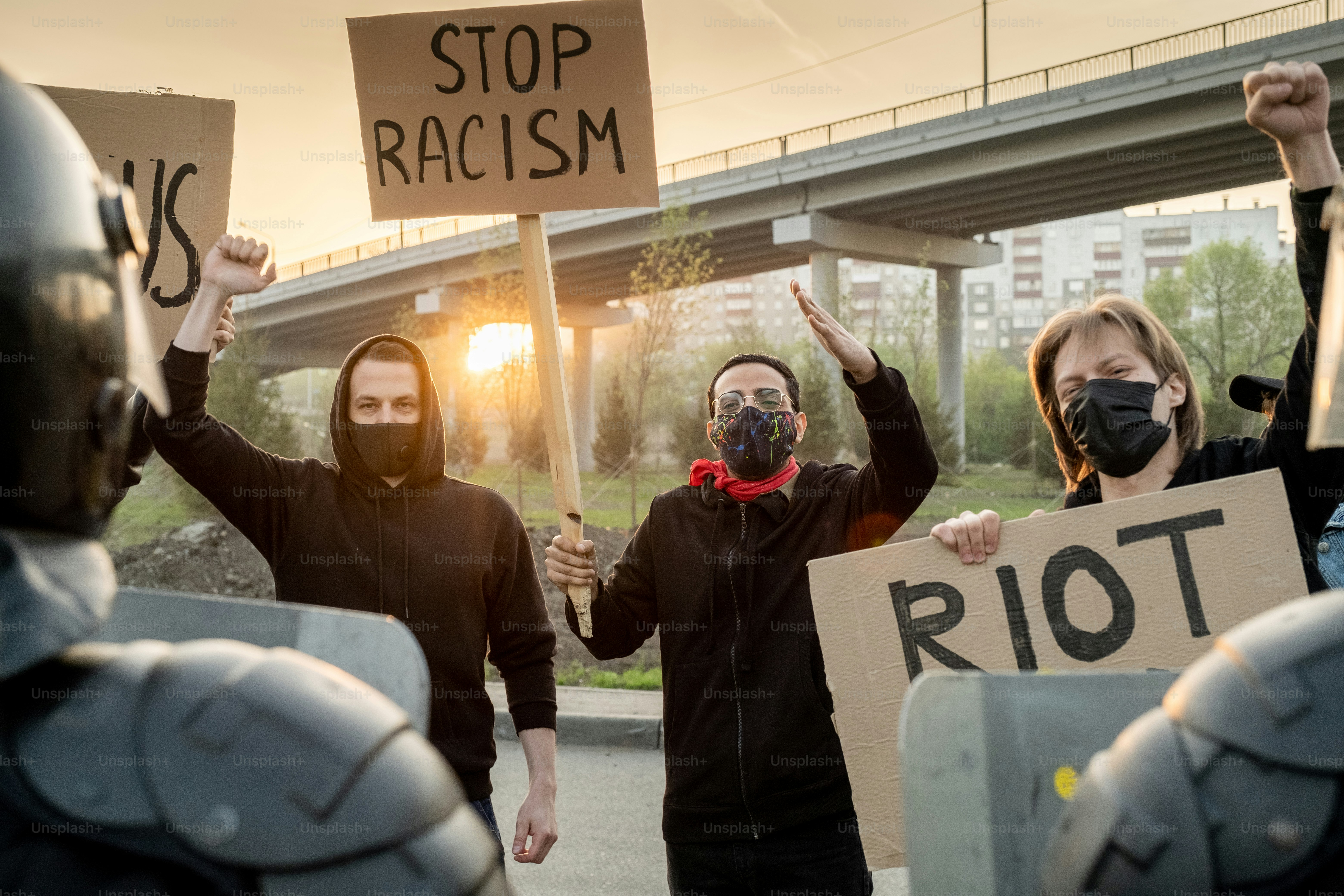 Group of displeased crowd in masks raising fists and screaming while ...