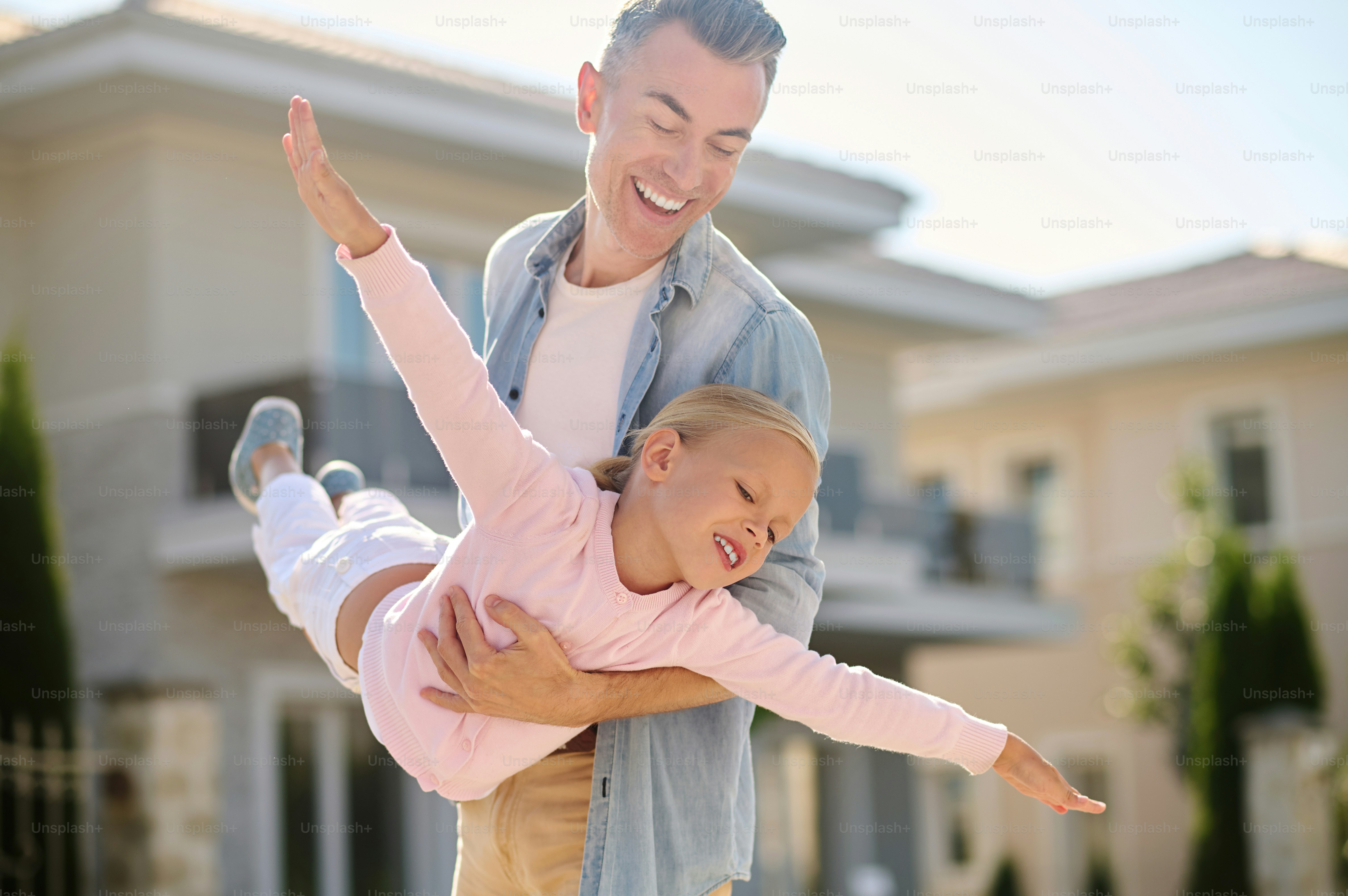 Like an airplane. Happy dad holding his inspired little blonde daughter ...