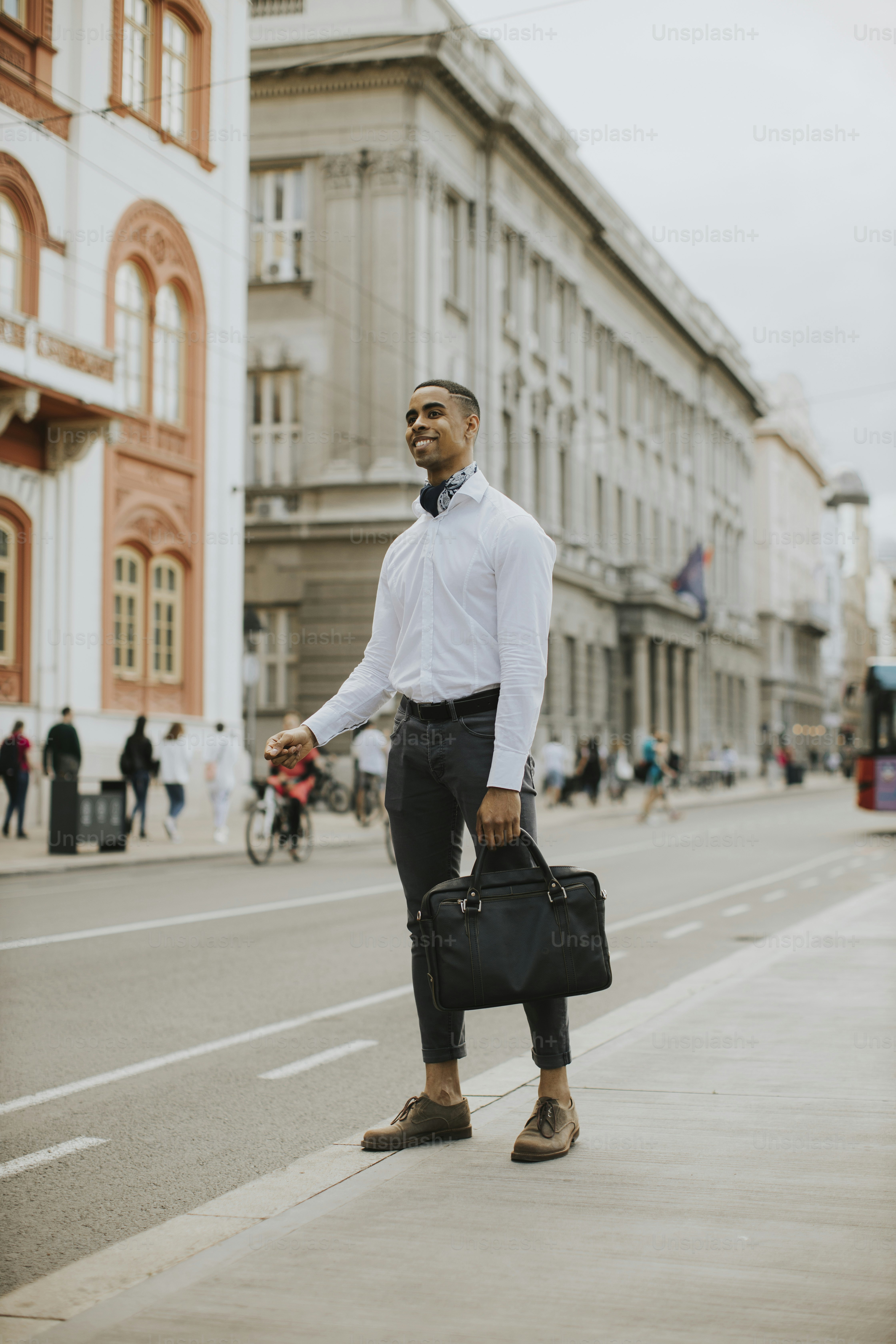 Handsome young African American businessman waitng a taxi on a street ...
