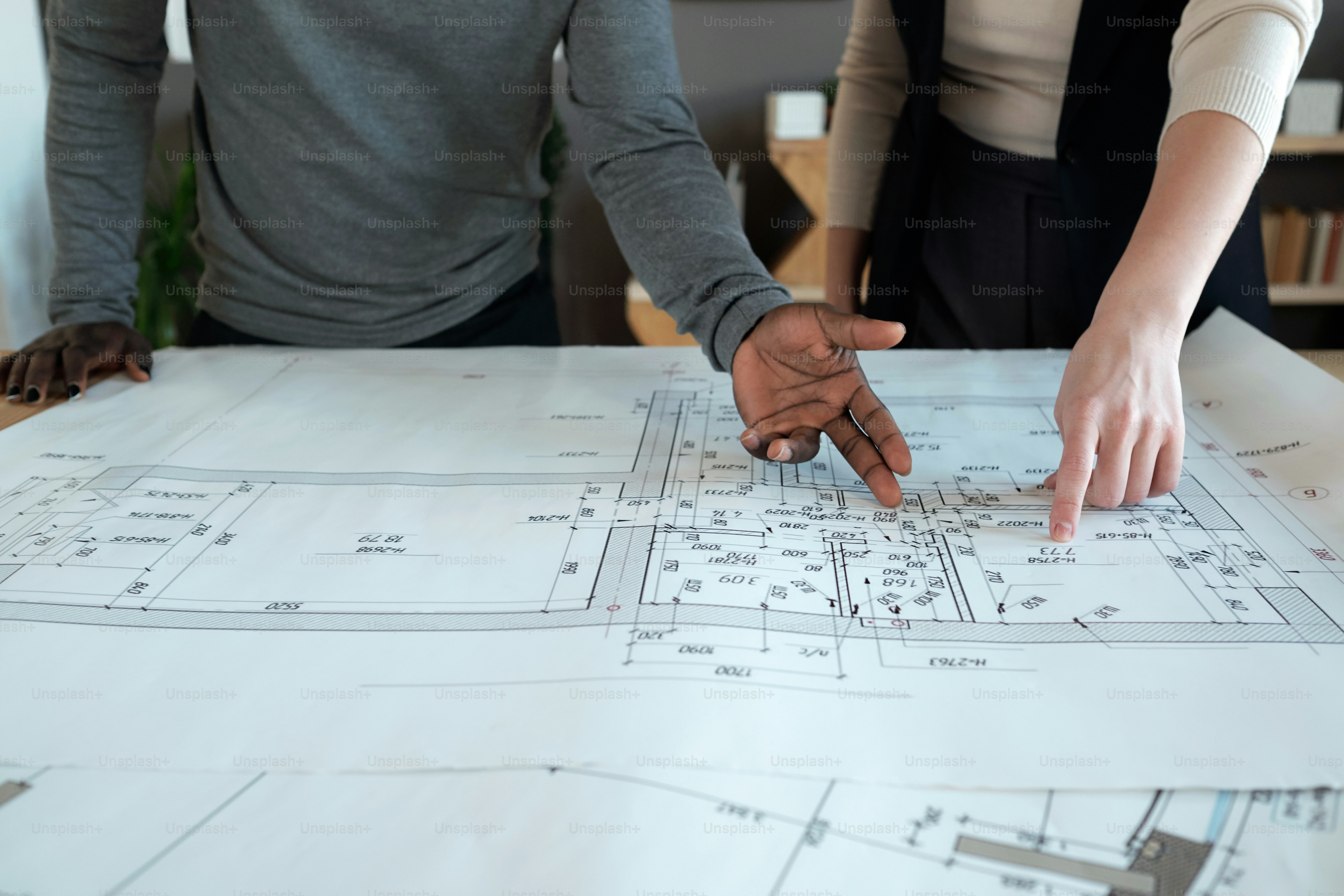 Hands of two intercultural architects pointing at sketch representing ...