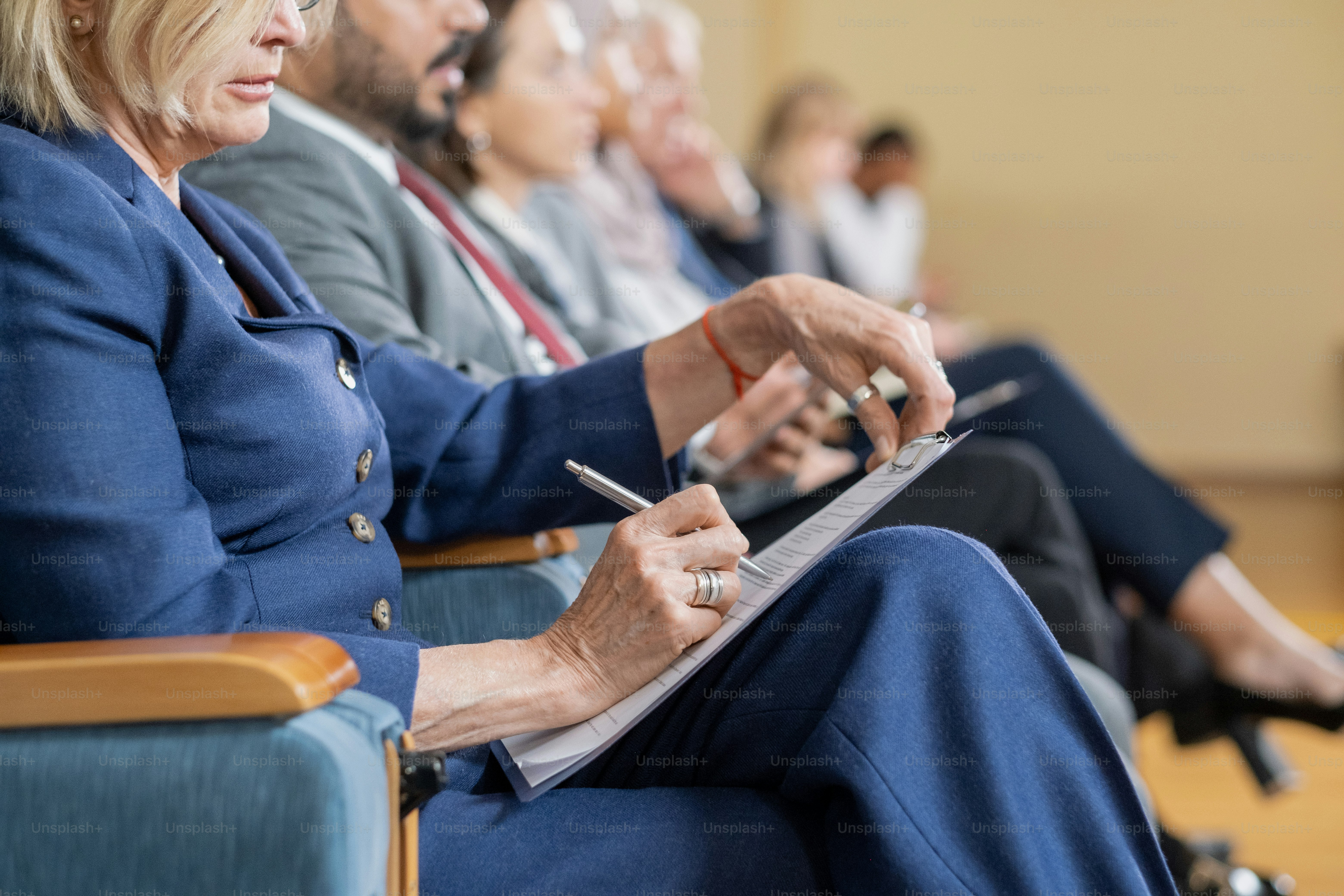 Row of foreign delegates listening to lecture and making notes while ...