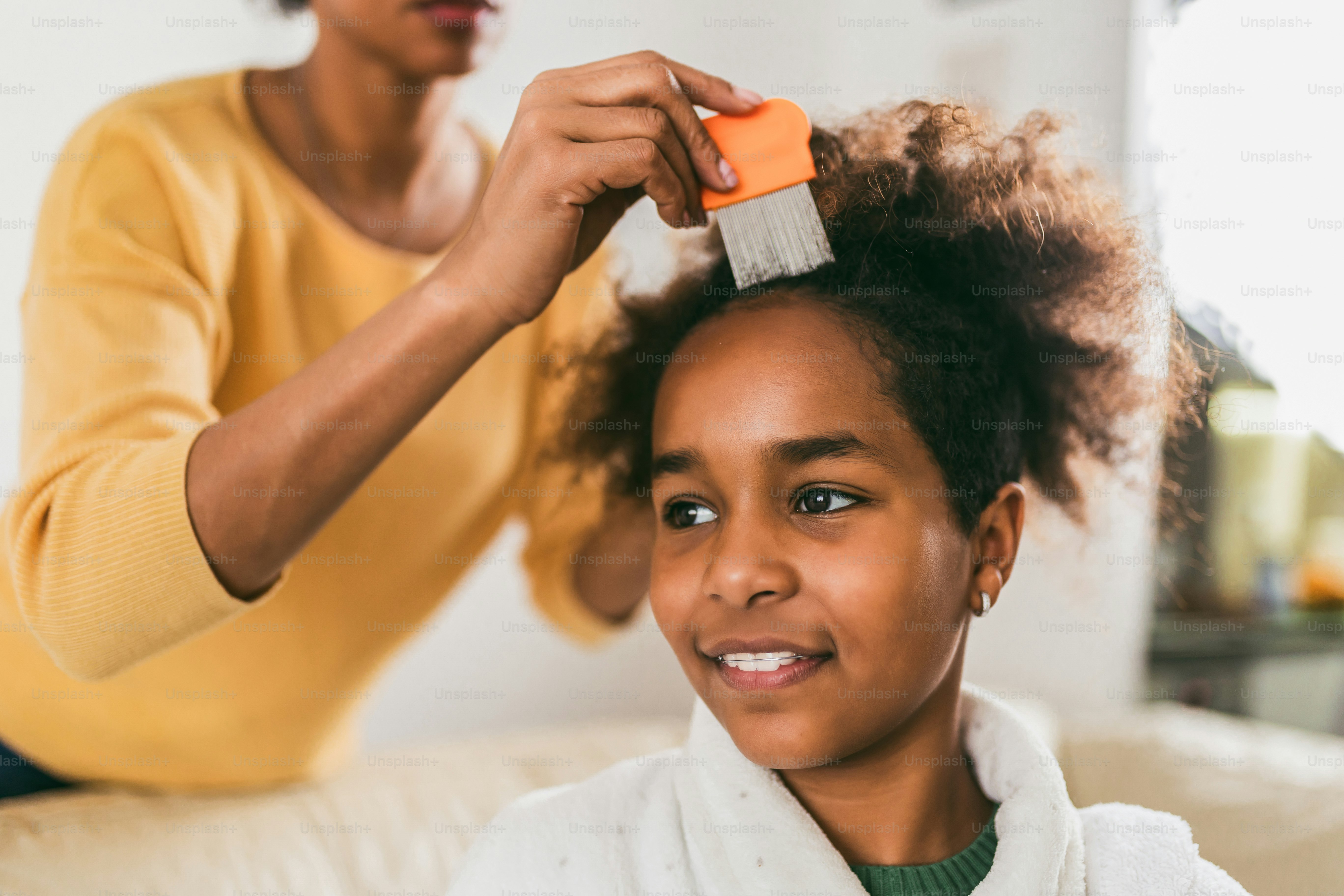 Mother doing head lice cleaning on her daughter curly hair. photo ...