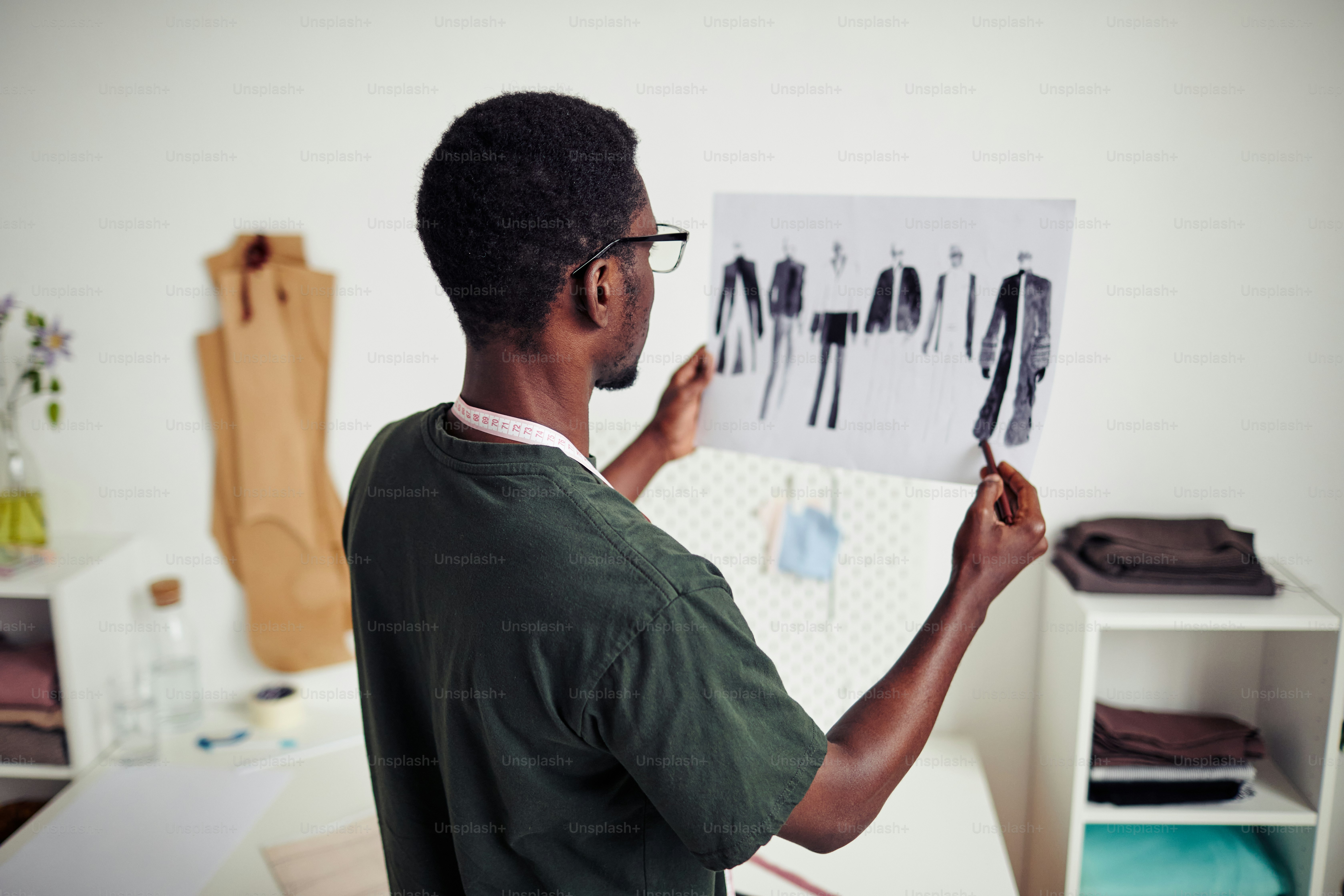 Young black fashion designer holding sheet of skeches for new ...