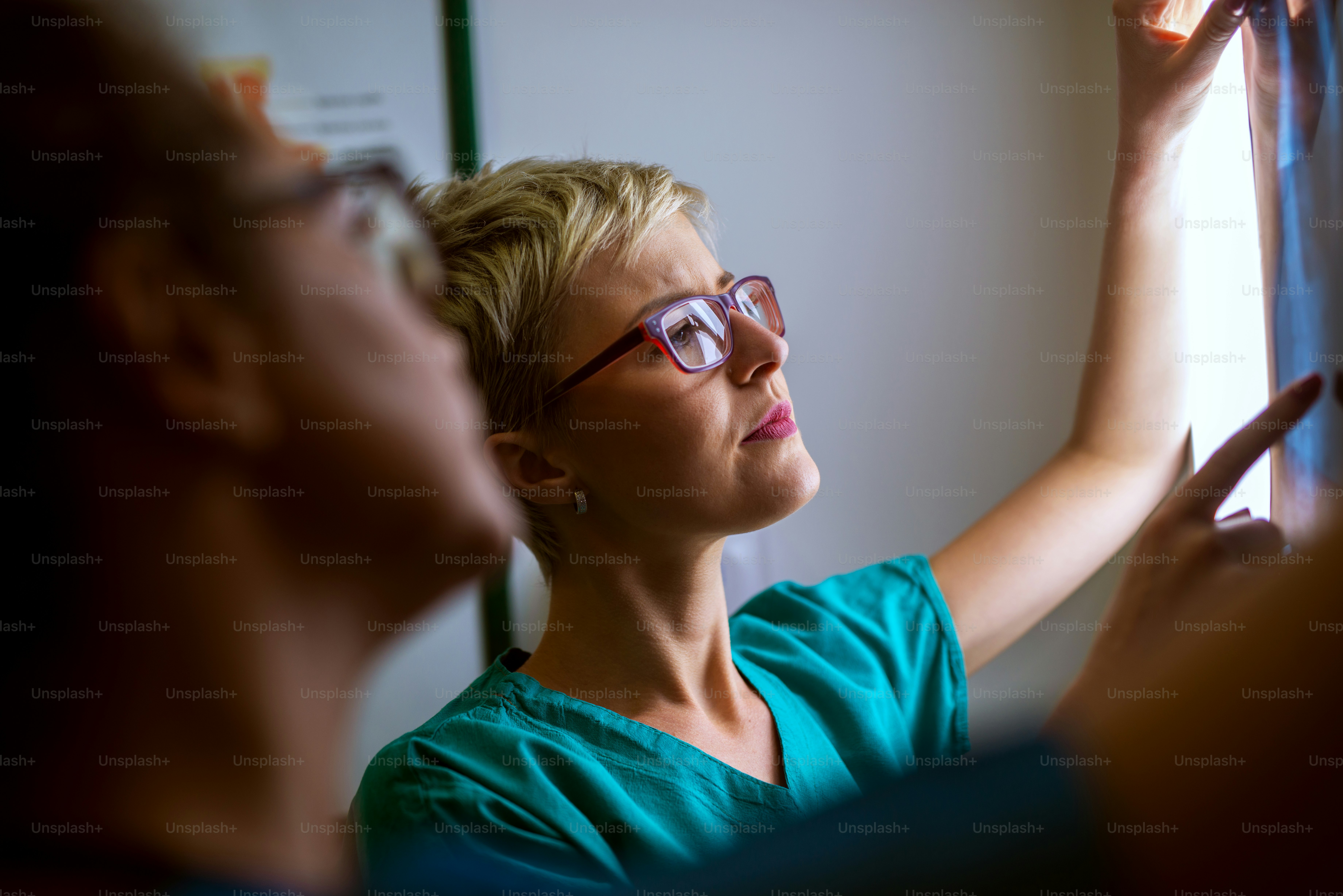 Close up side view of two professional nurses with eyeglasses checking ...