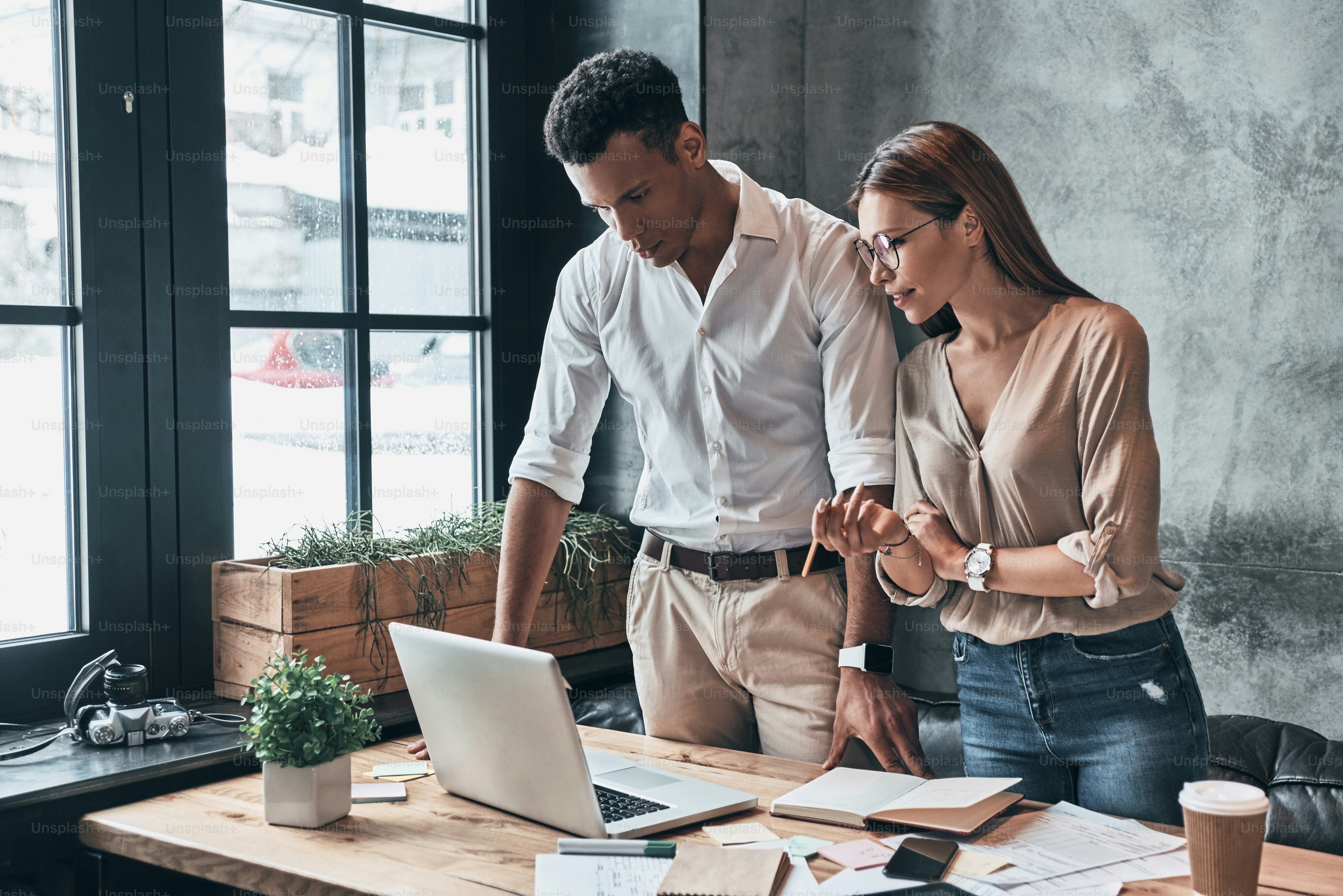 Young confident business people using computer and smiling while ...