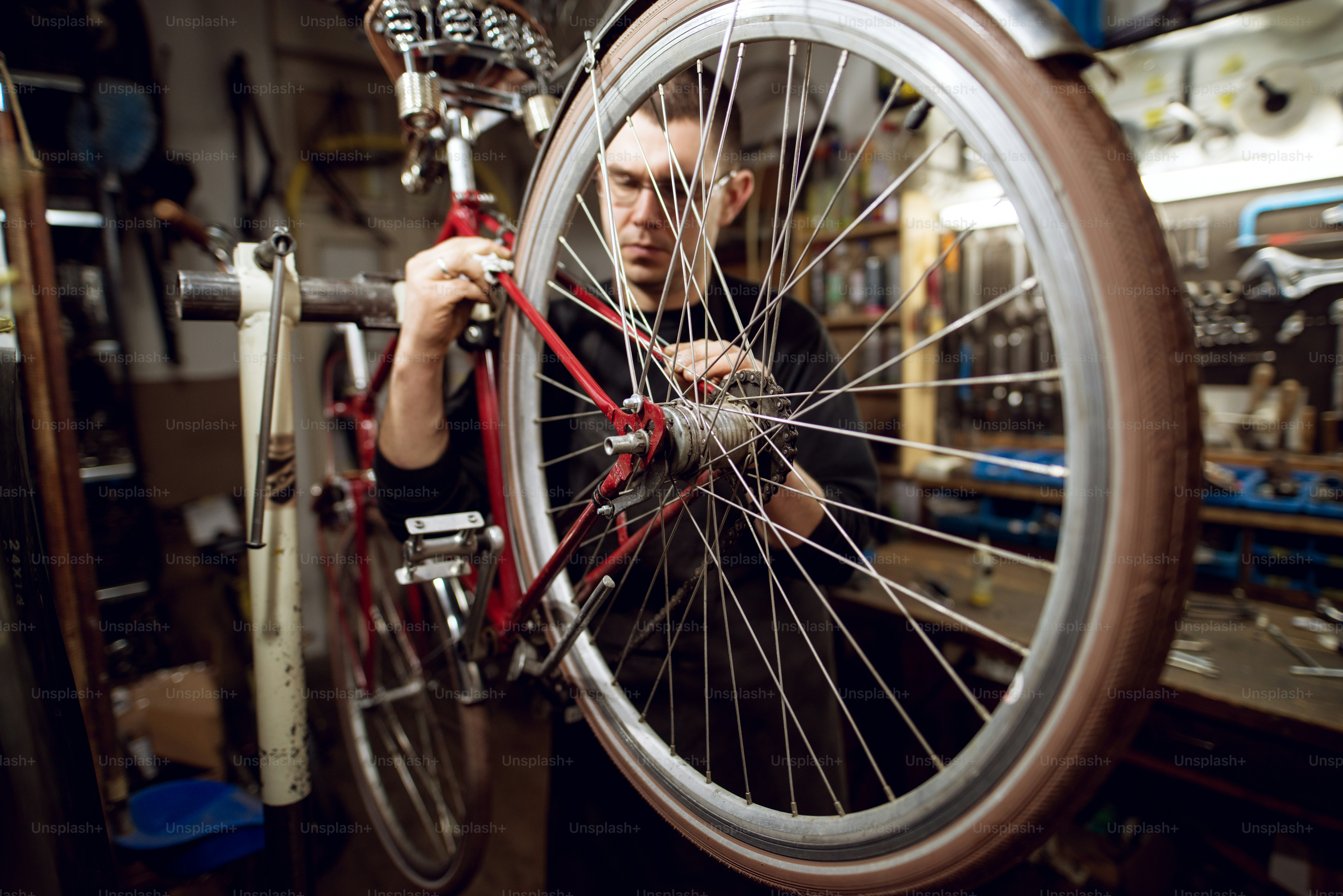 Professional young man cleaning bicycle rear bar in the workshop. photo ...