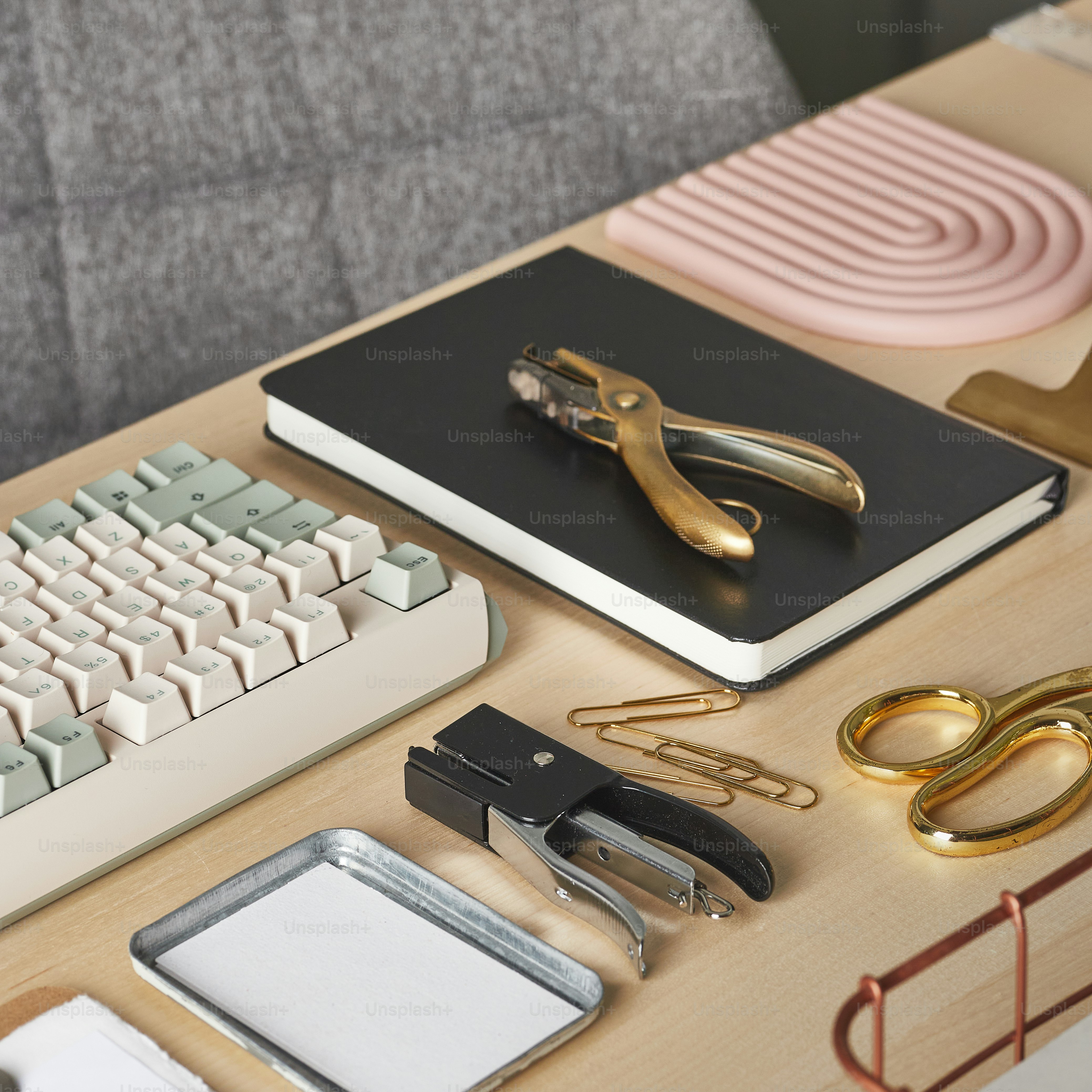 A desk with a keyboard, binder, scissors, and other office supplies ...