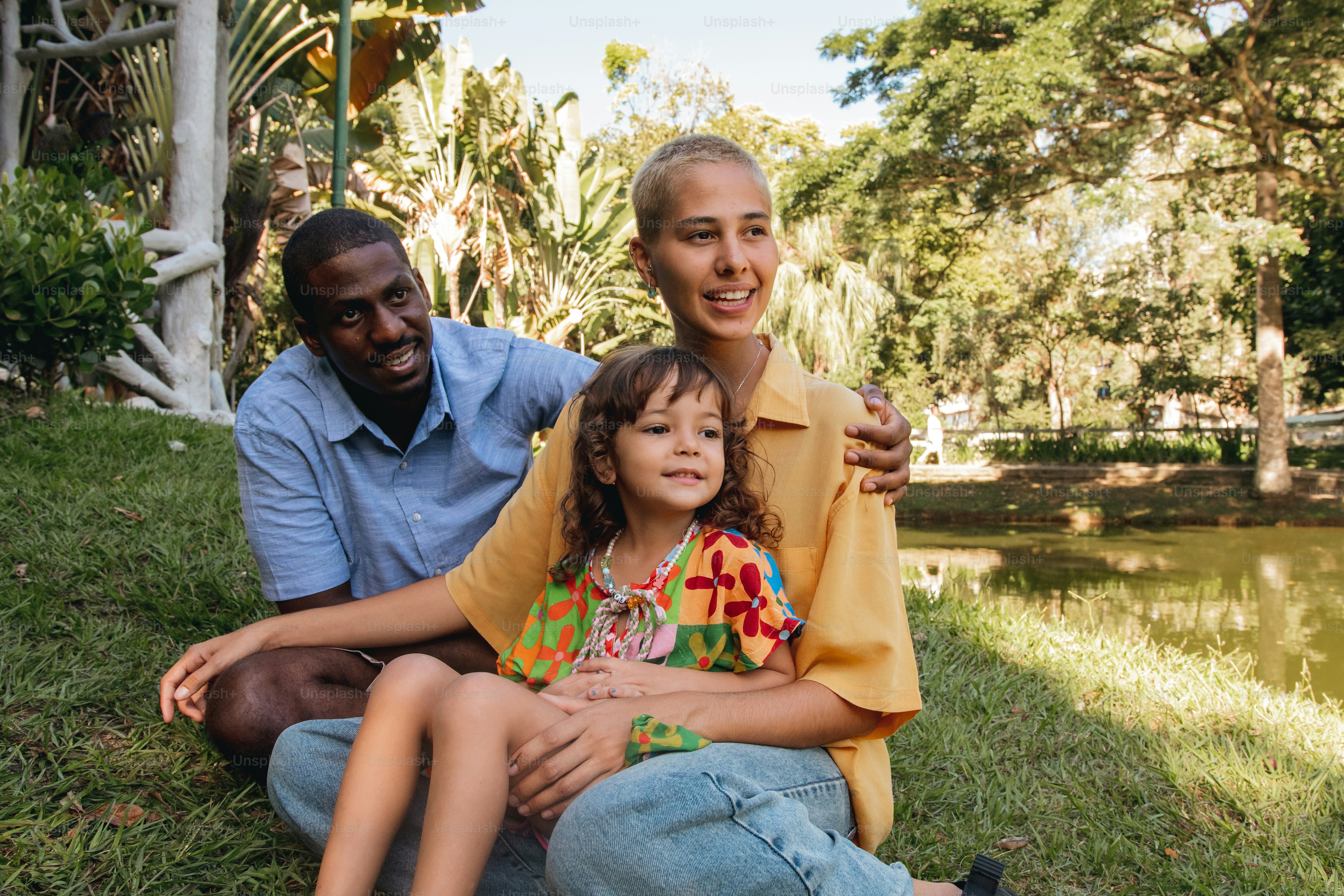 A man and a woman sitting on the grass with a little girl photo ...