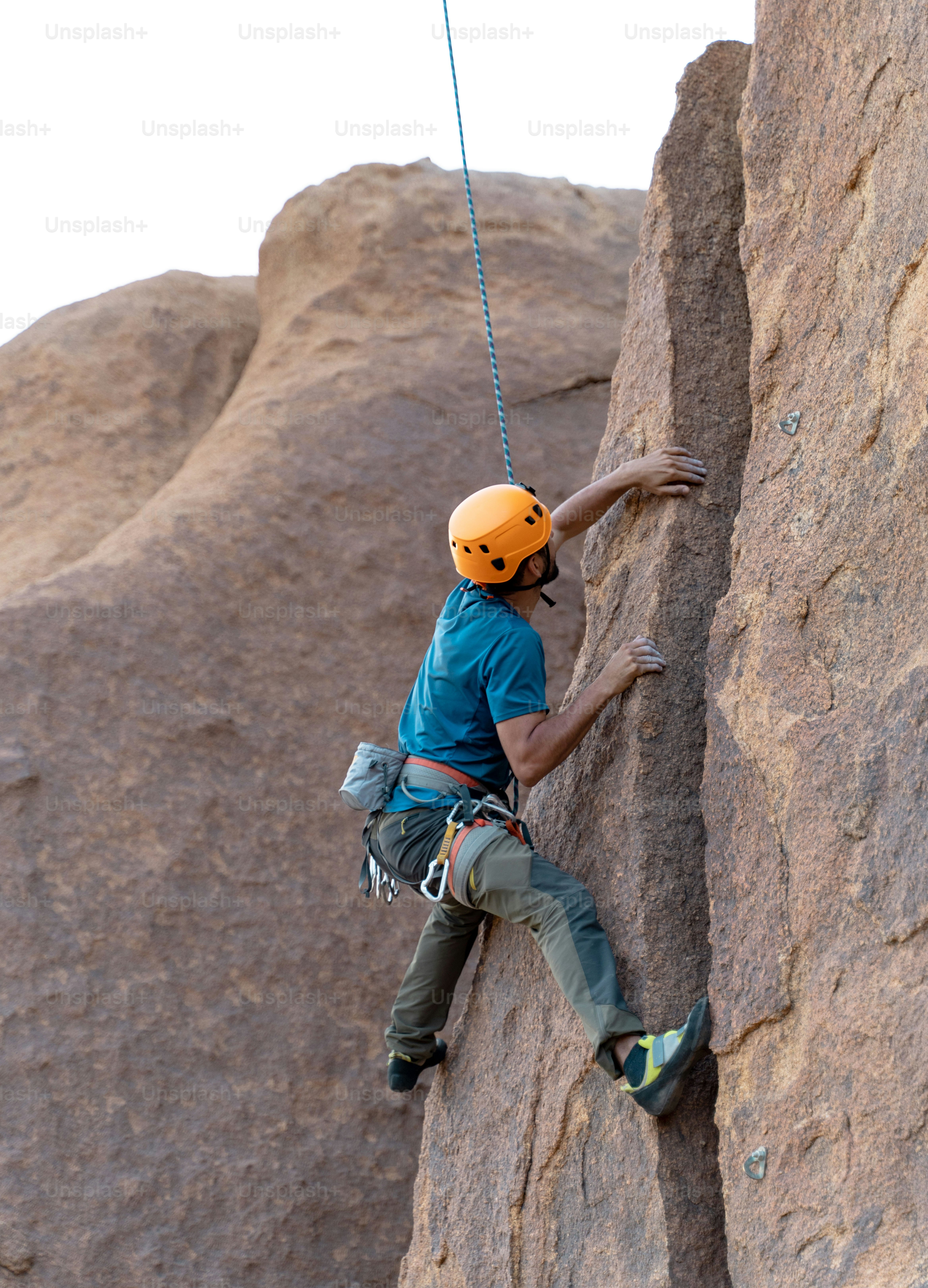 A man climbing up the side of a large rock photo – Outdoor sports Image ...