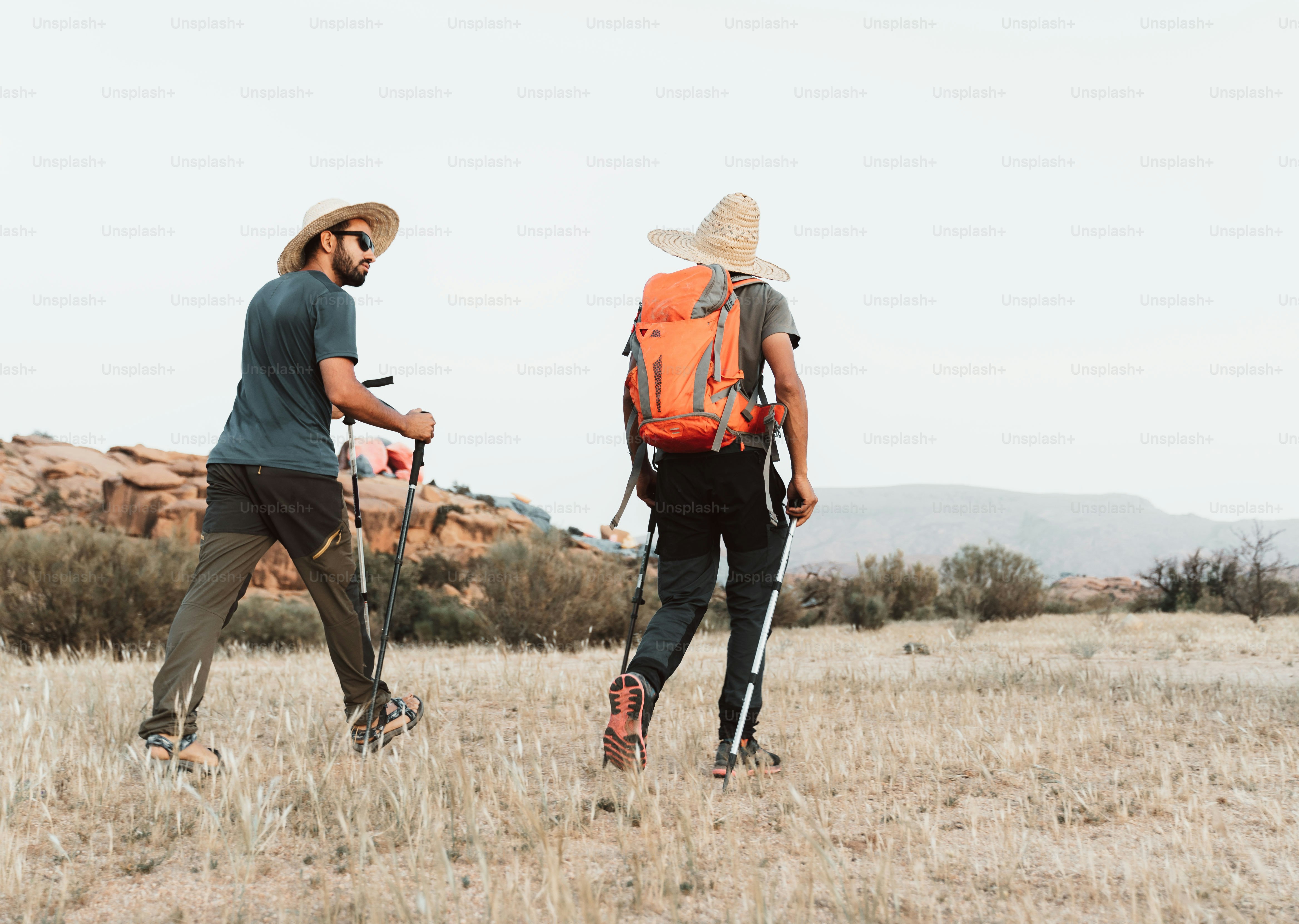 A couple of men walking across a dry grass field photo – Summer travel ...