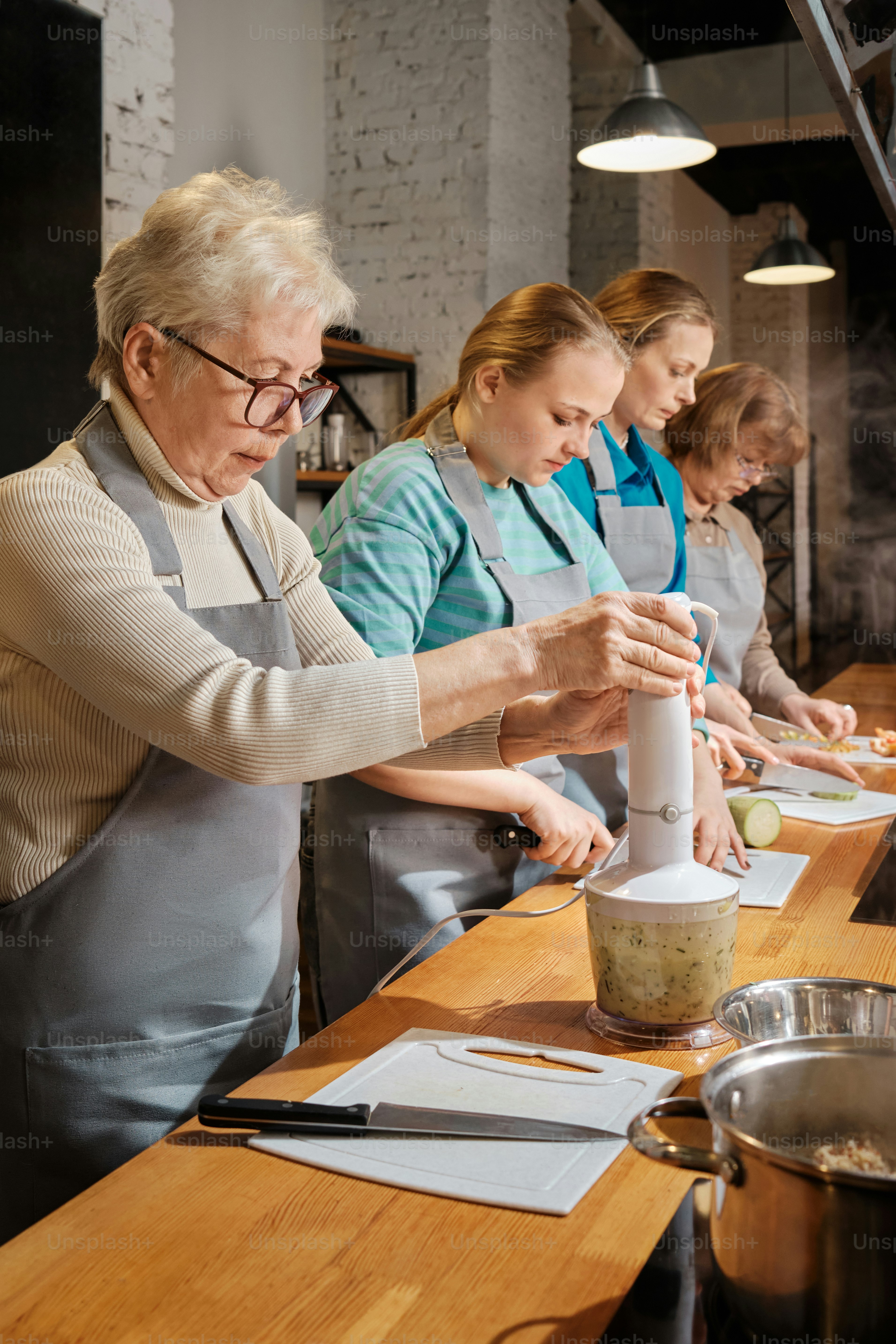 A group of people standing around a counter preparing food photo ...