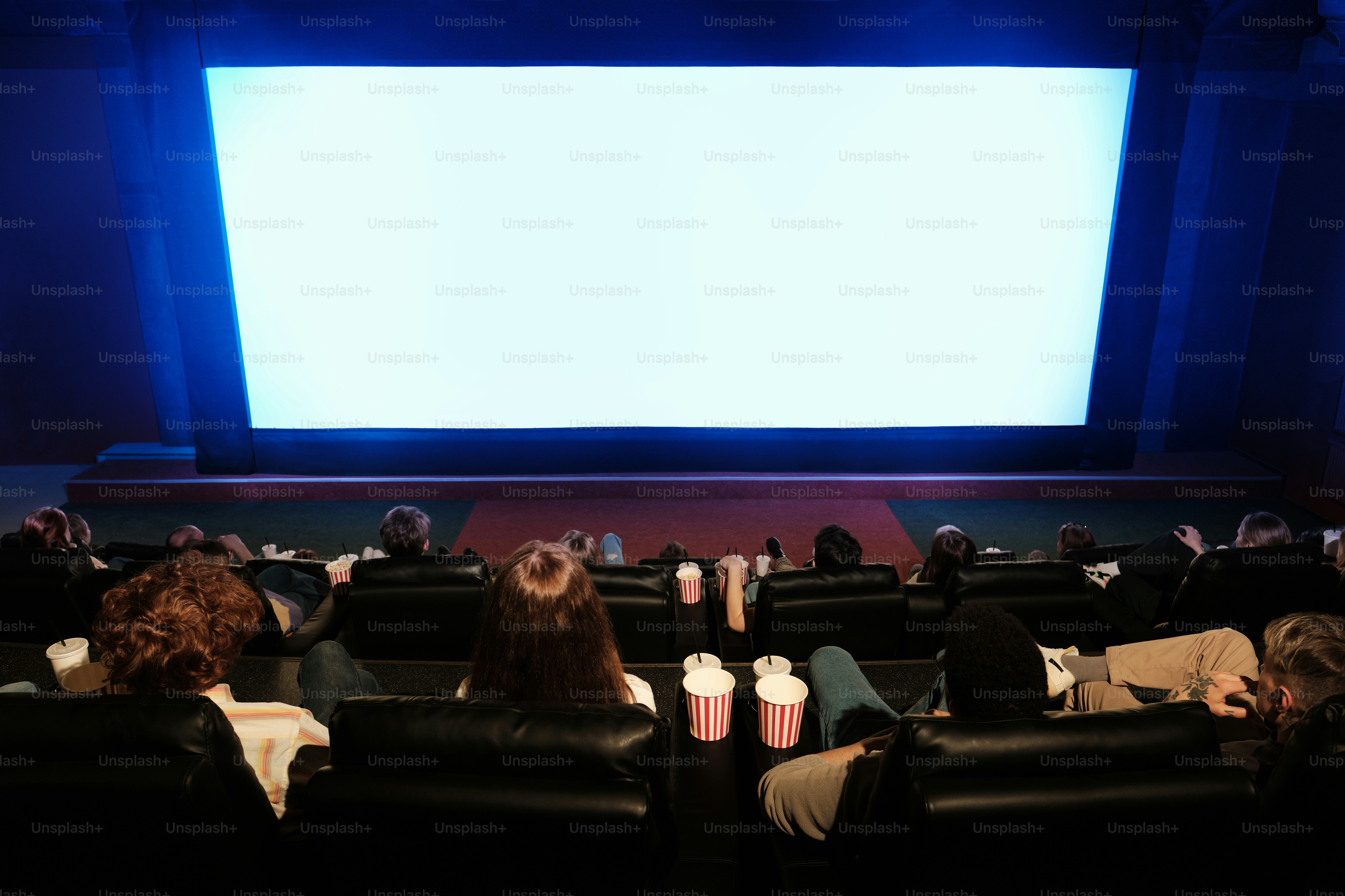 A group of people sitting in chairs watching a movie photo – Cinema ...