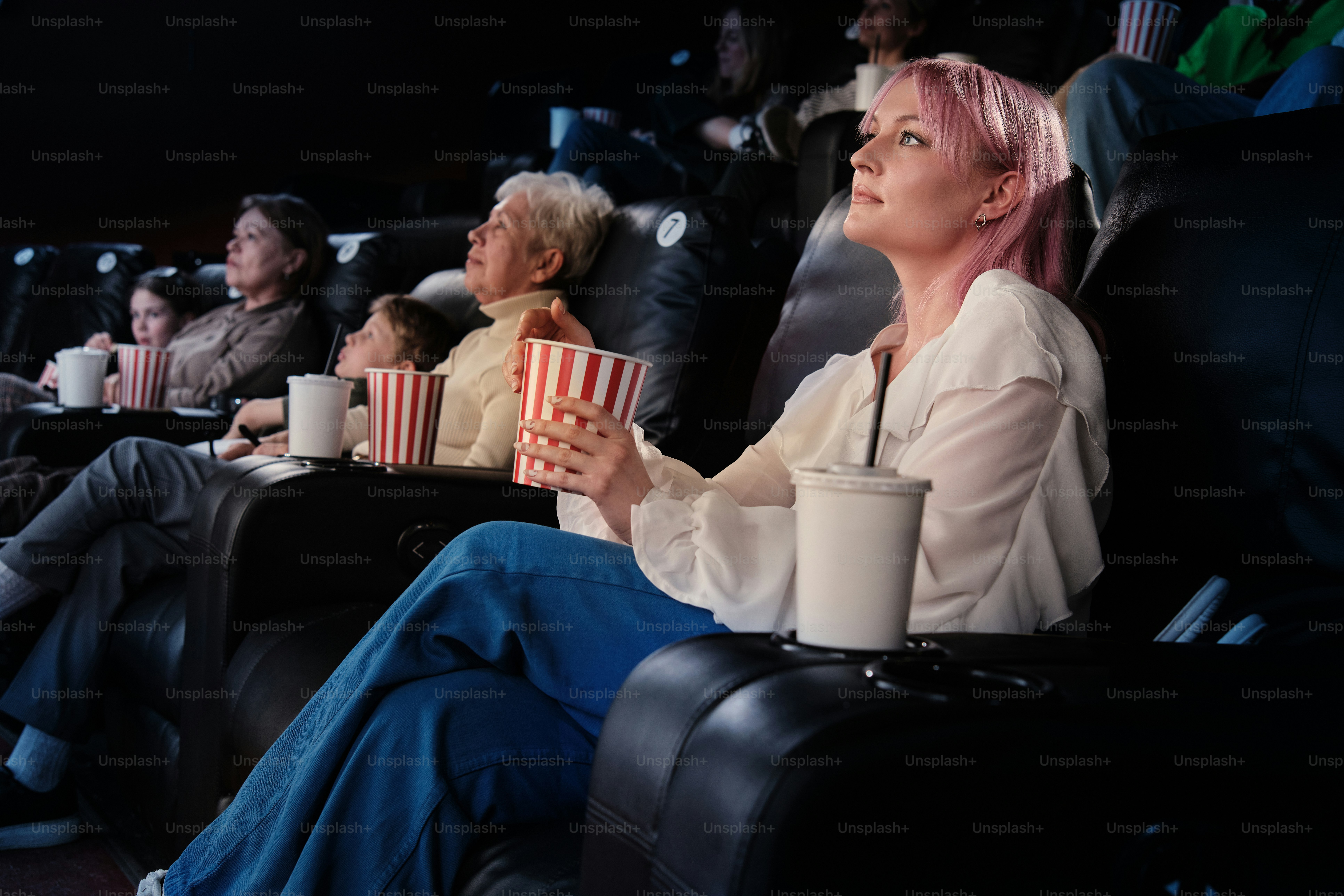 A group of people sitting in chairs watching a movie photo – Different ...
