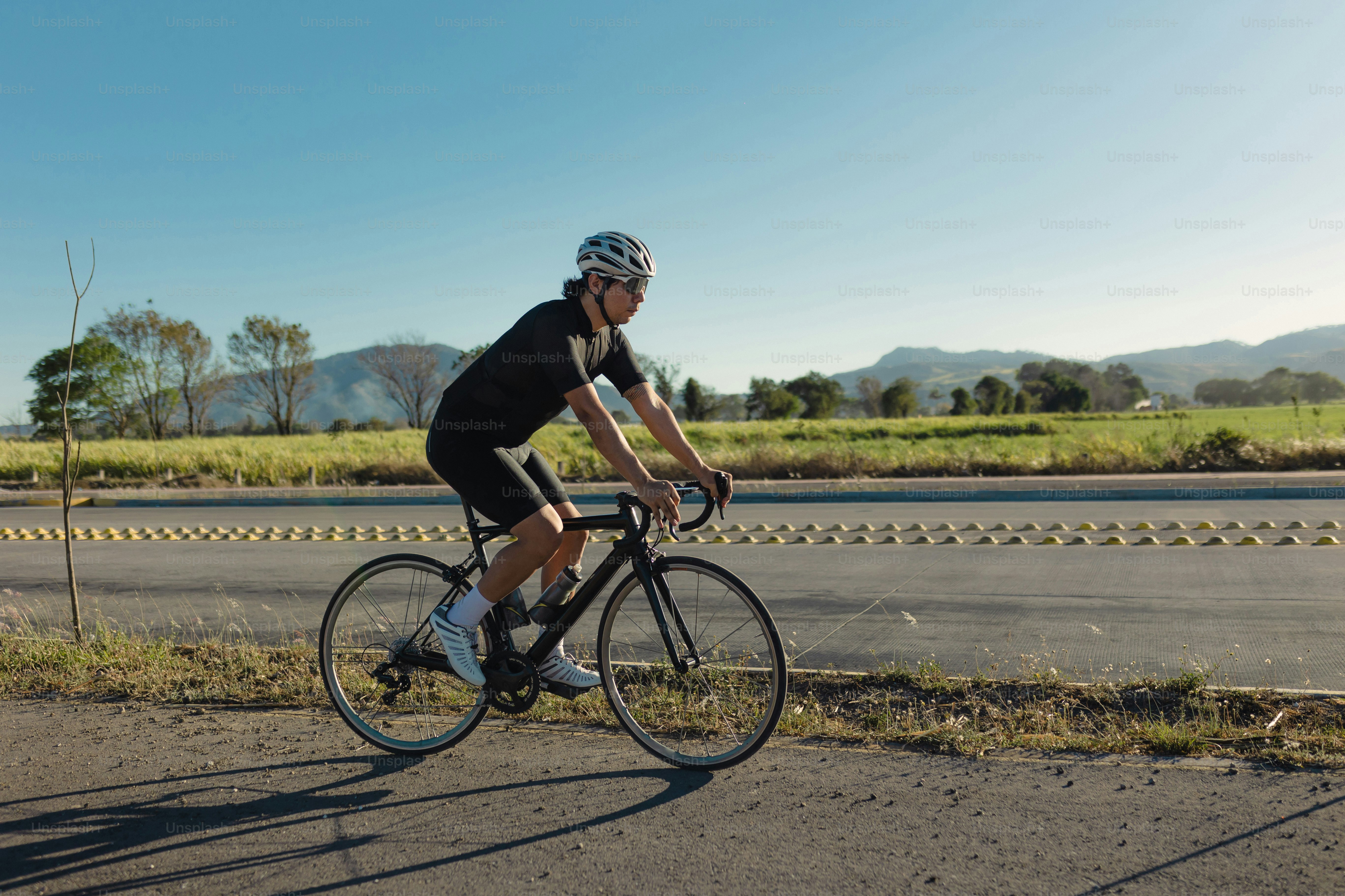 A man riding a bike down a road photo – Sport Image on Unsplash