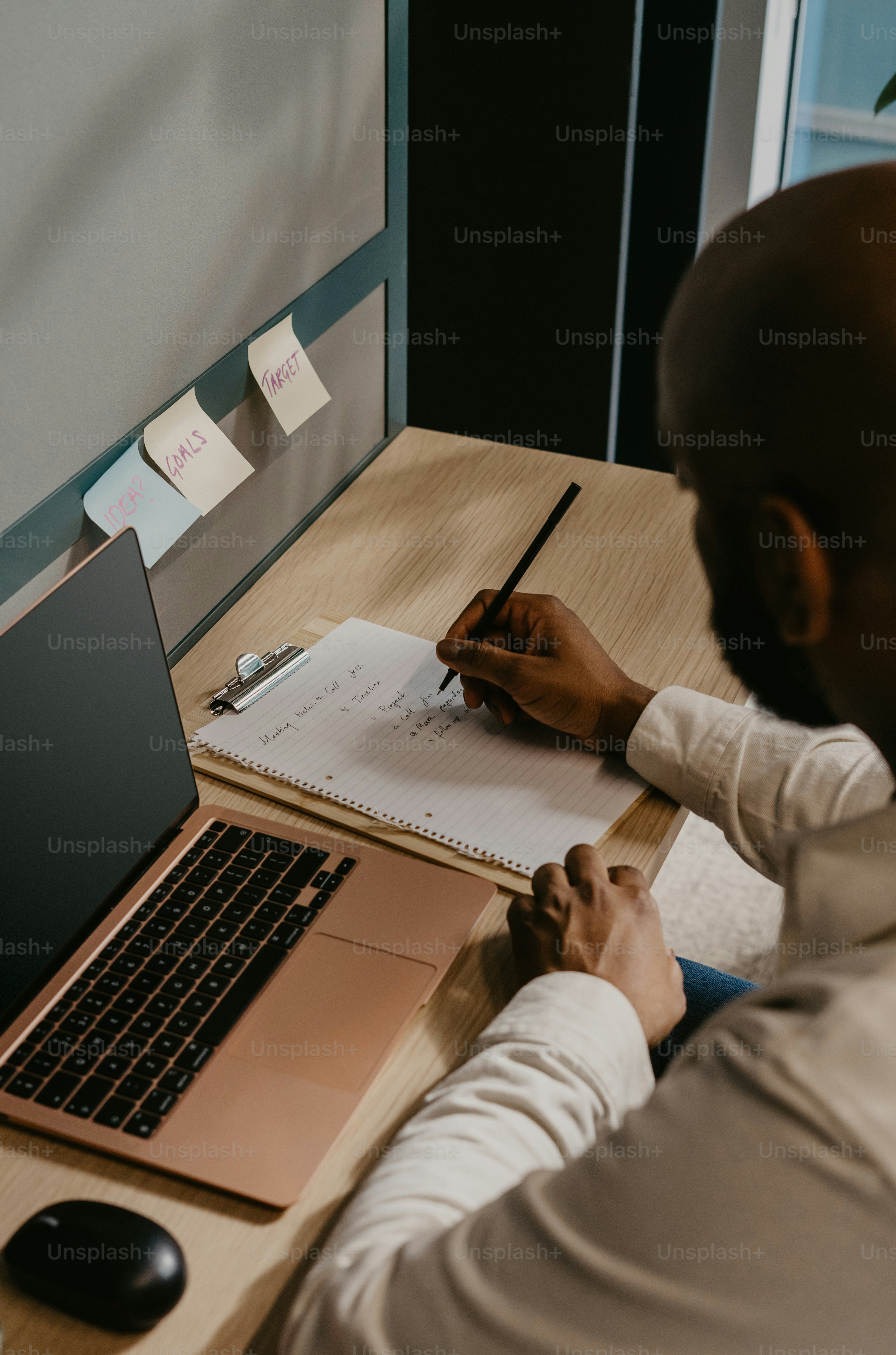 A man sitting at a desk writing on a piece of paper photo – Clipboard ...