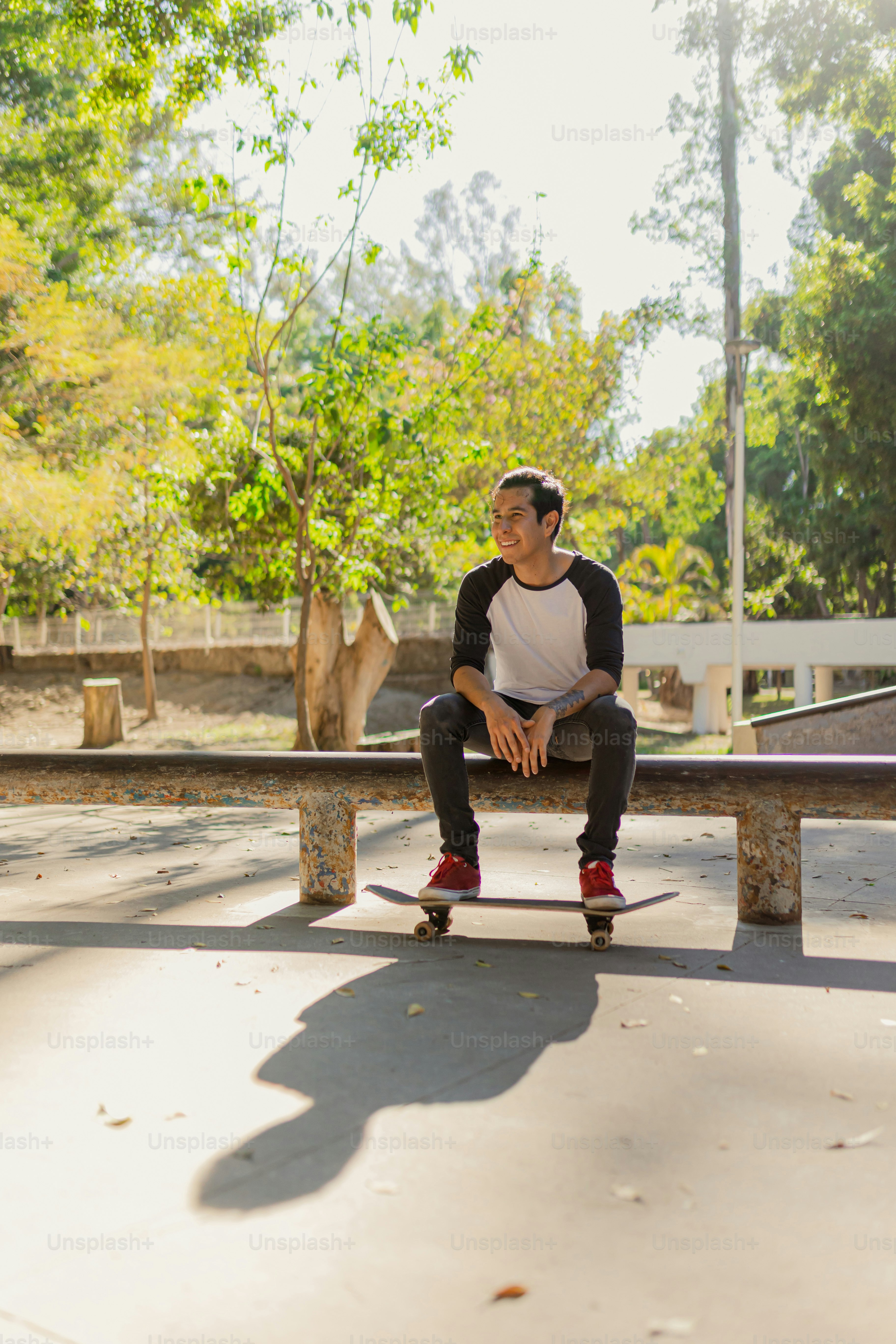 A man sitting on a bench with a skateboard photo – Skateboarding Image ...