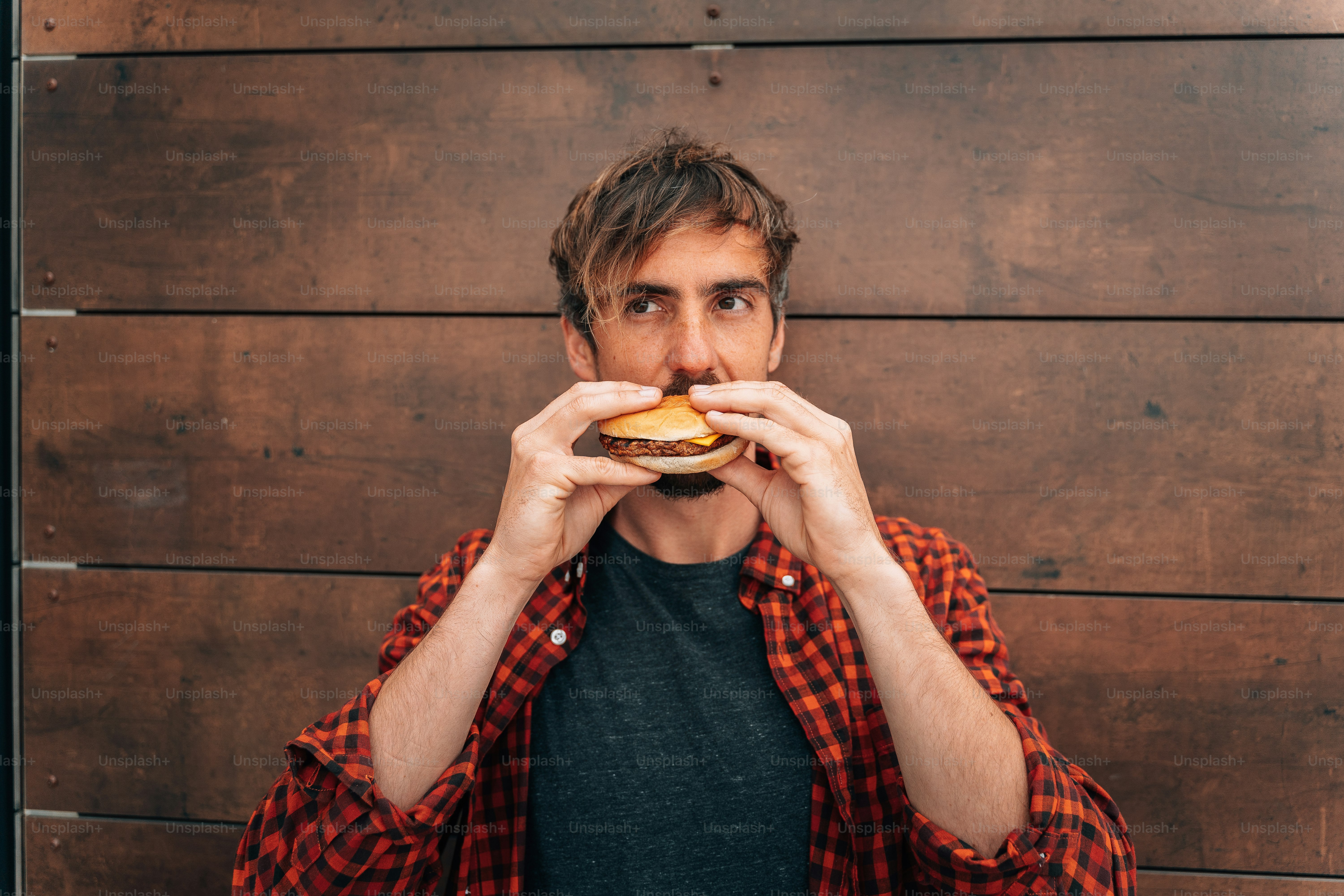 A man sitting on a ledge eating a donut photo – Burger Image on Unsplash