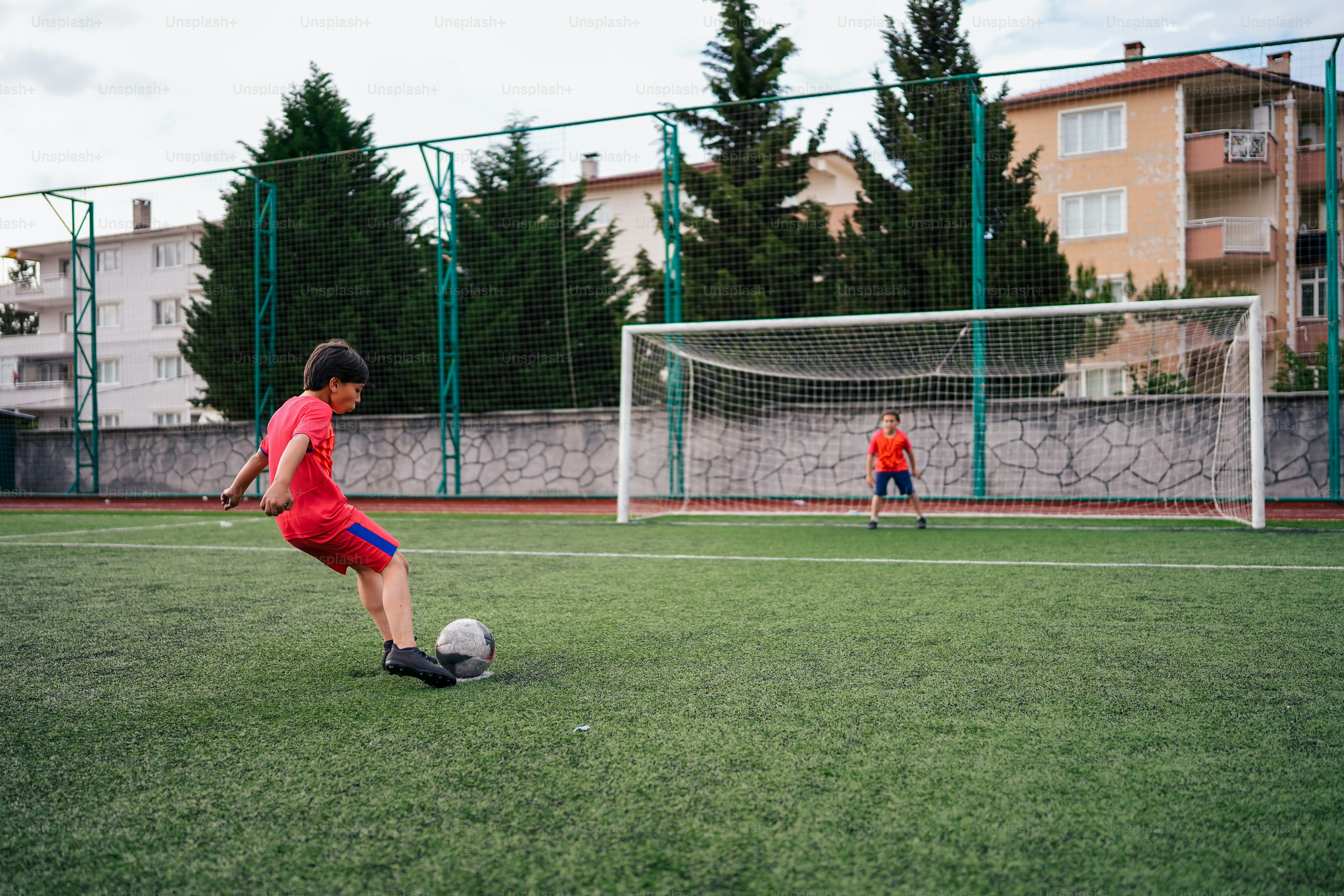 A young boy kicking a soccer ball on a field photo – Football ground ...