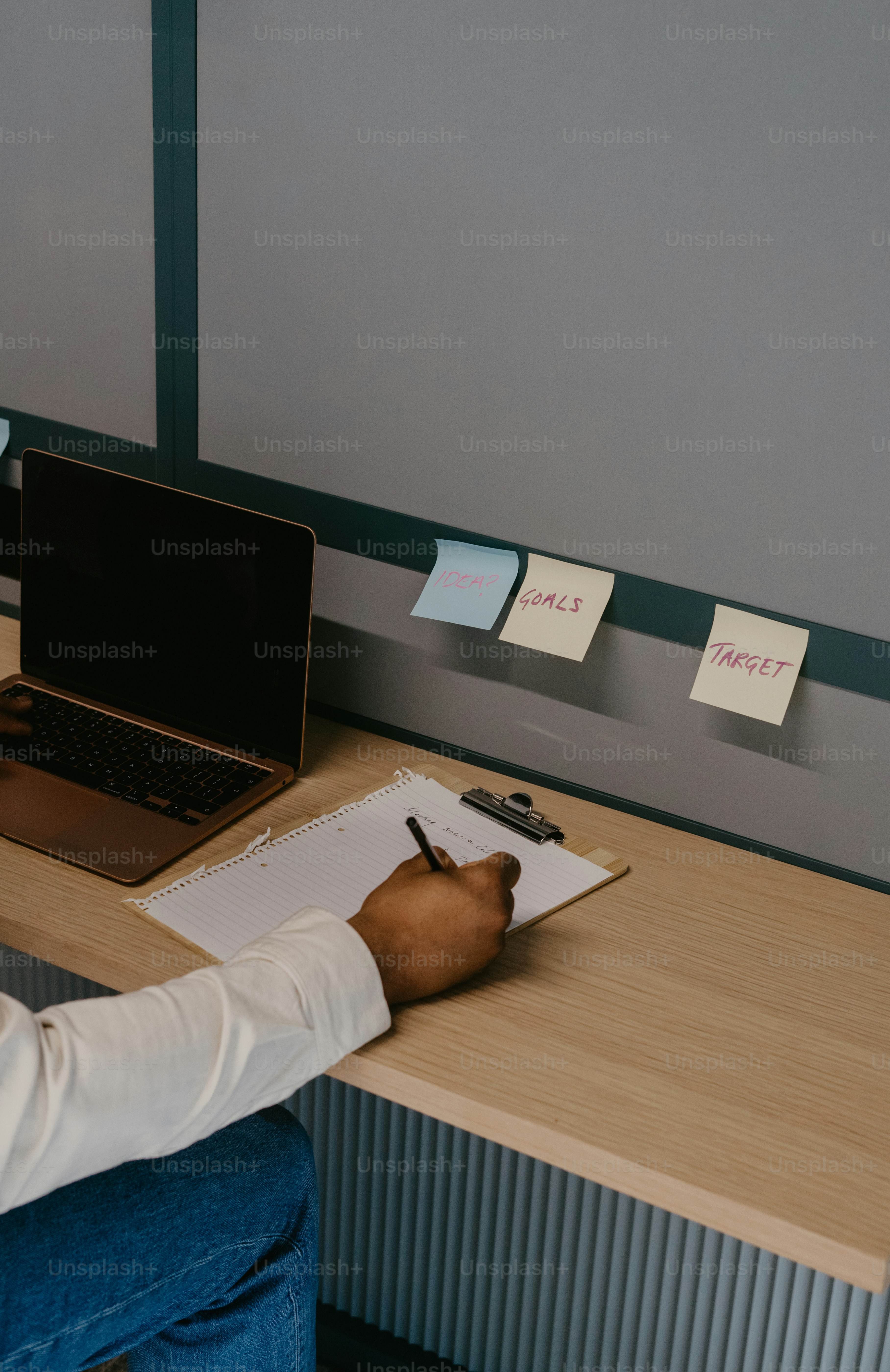 A man sitting at a desk writing on a piece of paper photo – Swot Image ...