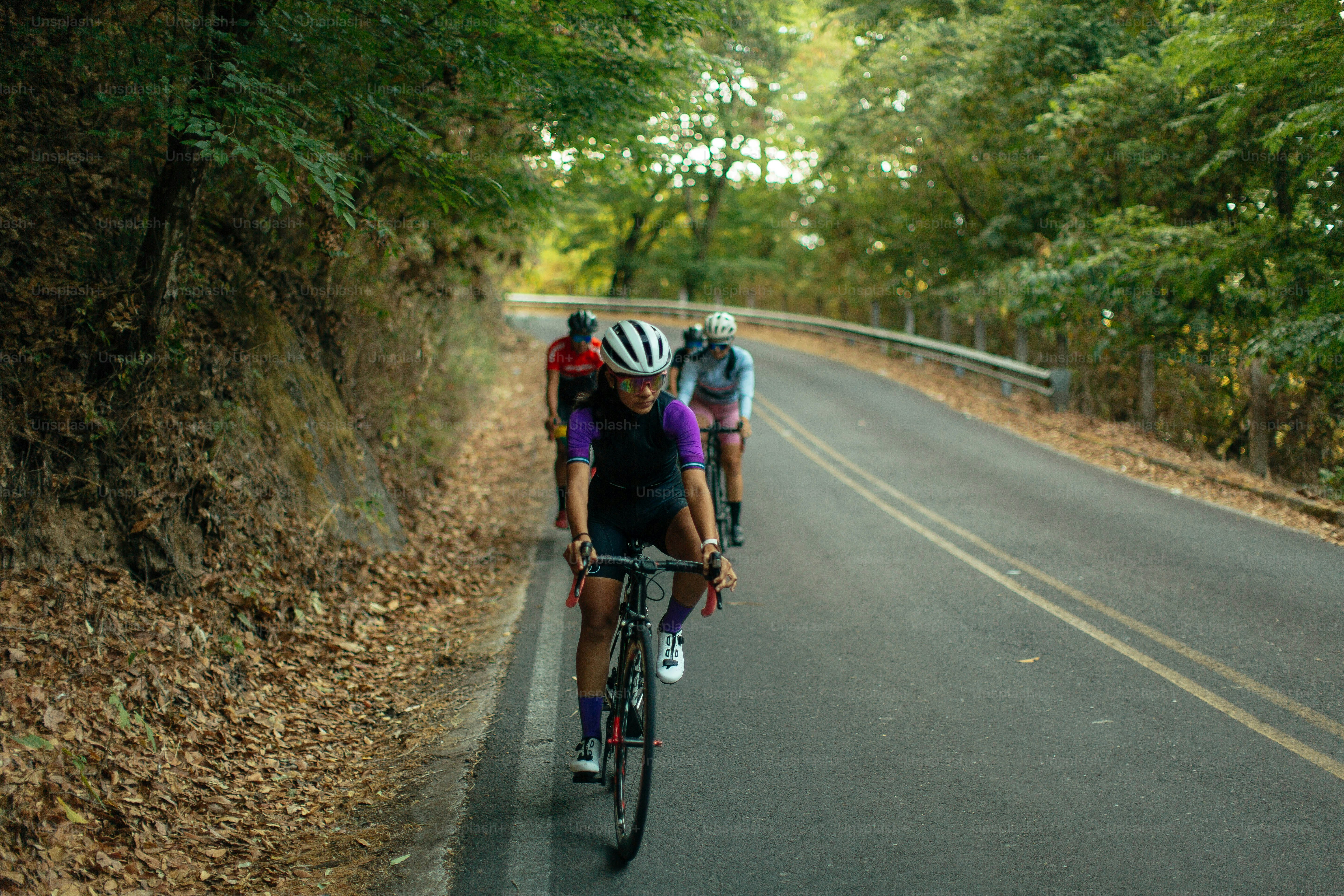 A group of people riding bikes down a street photo – Cyclists Image on ...
