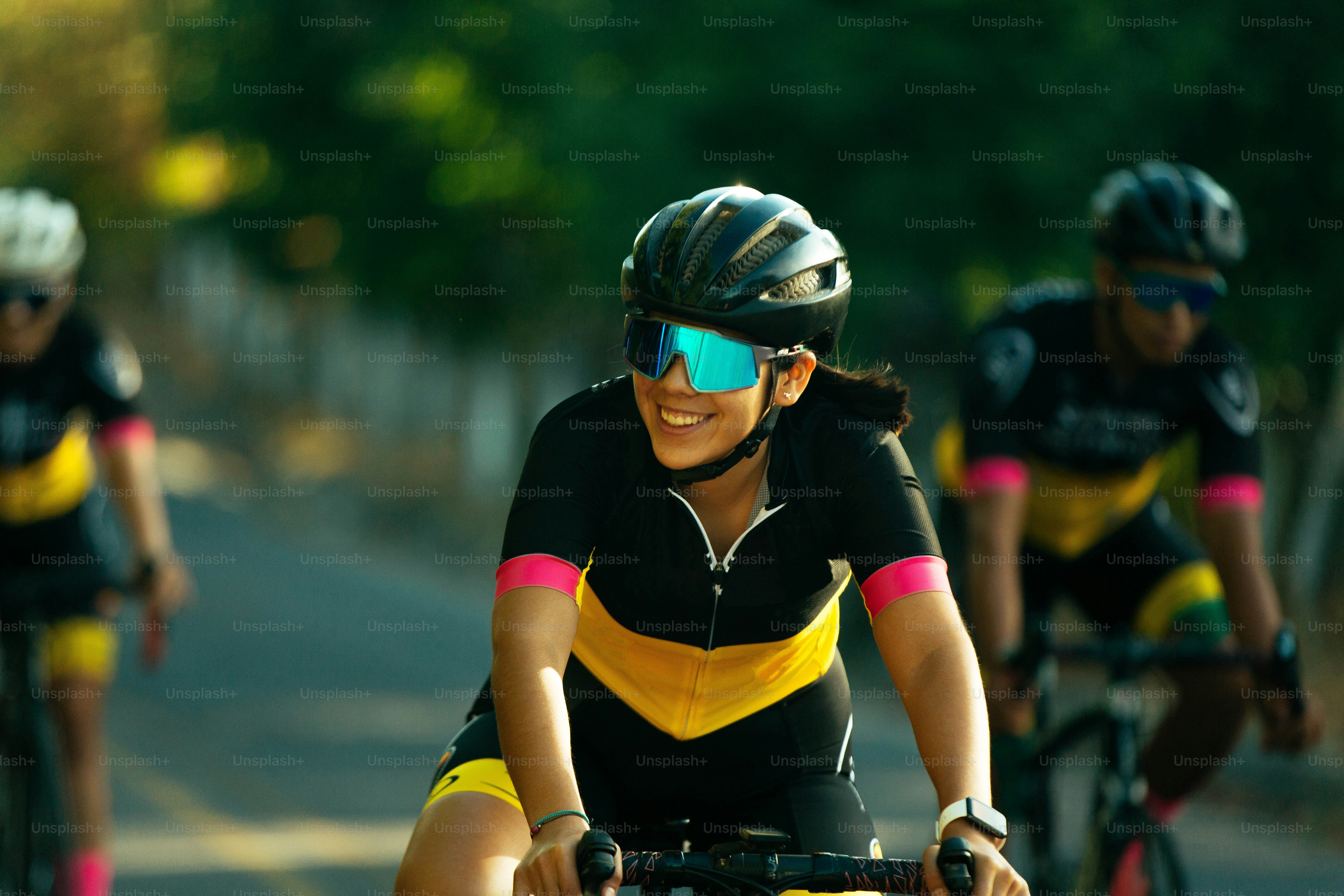 A couple of people riding bikes down a road photo – Group pf cyclists ...