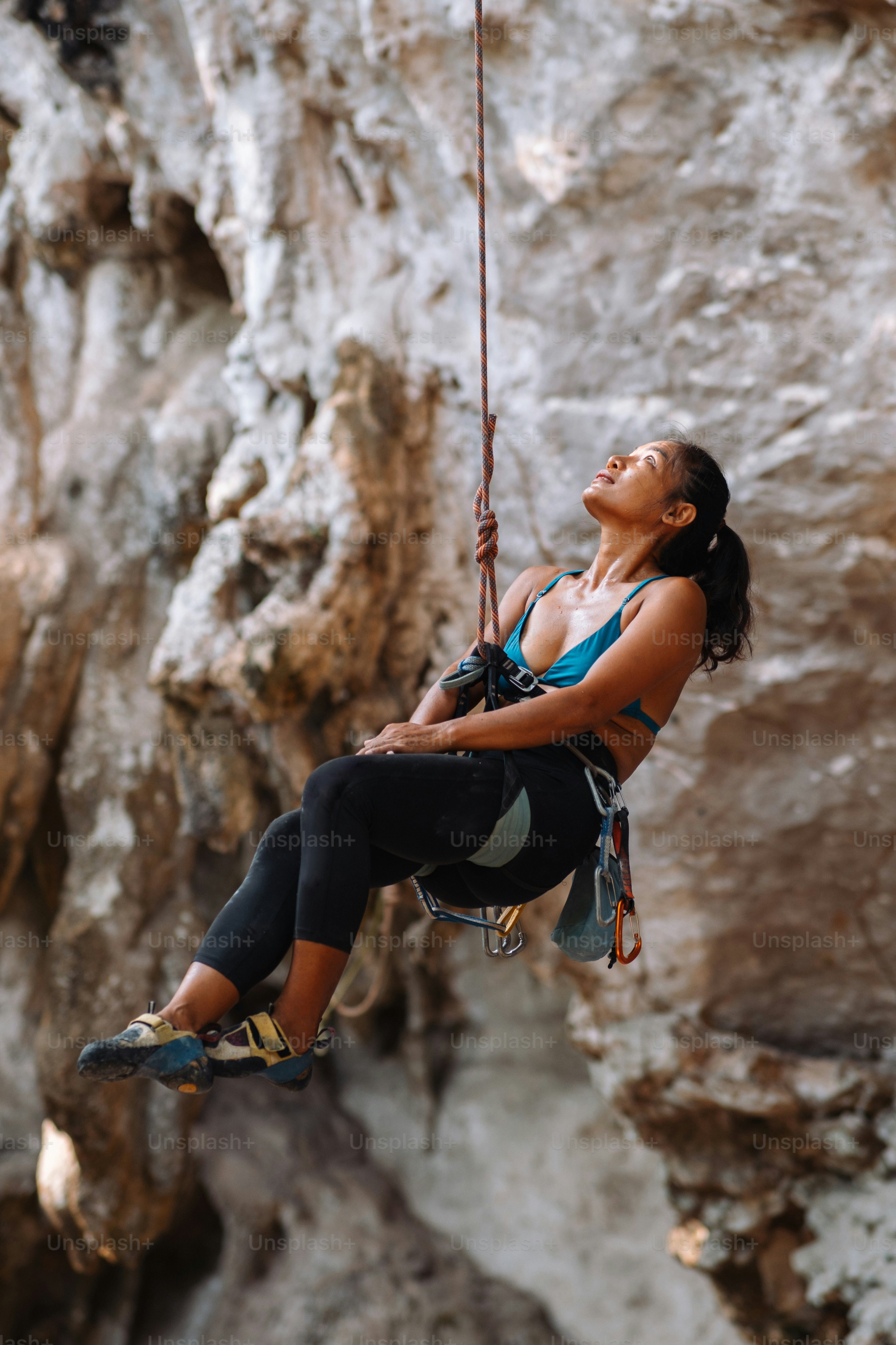 A woman hanging from a rope in front of a cliff photo – Climbing Image ...