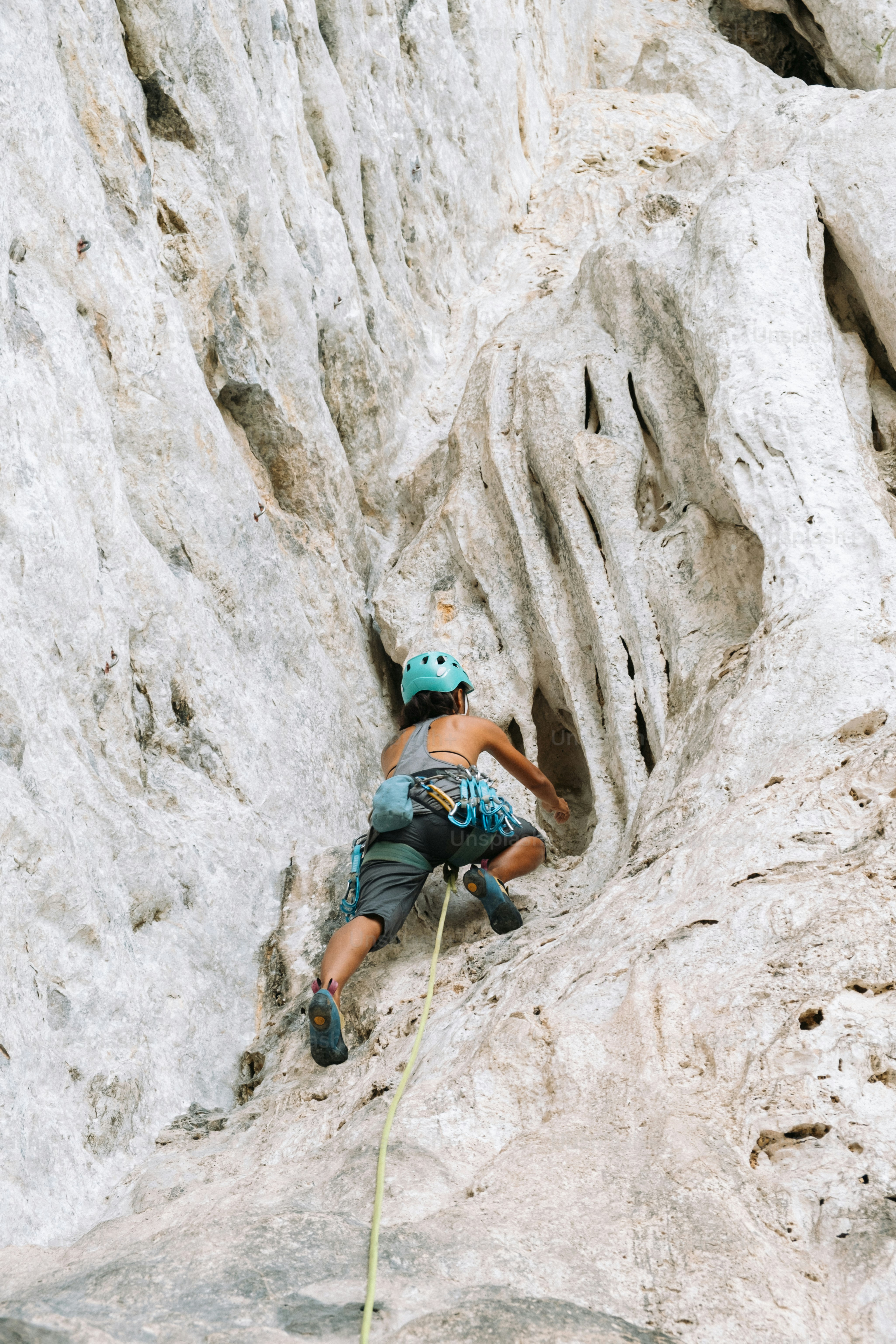 A woman climbing up the side of a mountain photo – Rock climbing Image ...