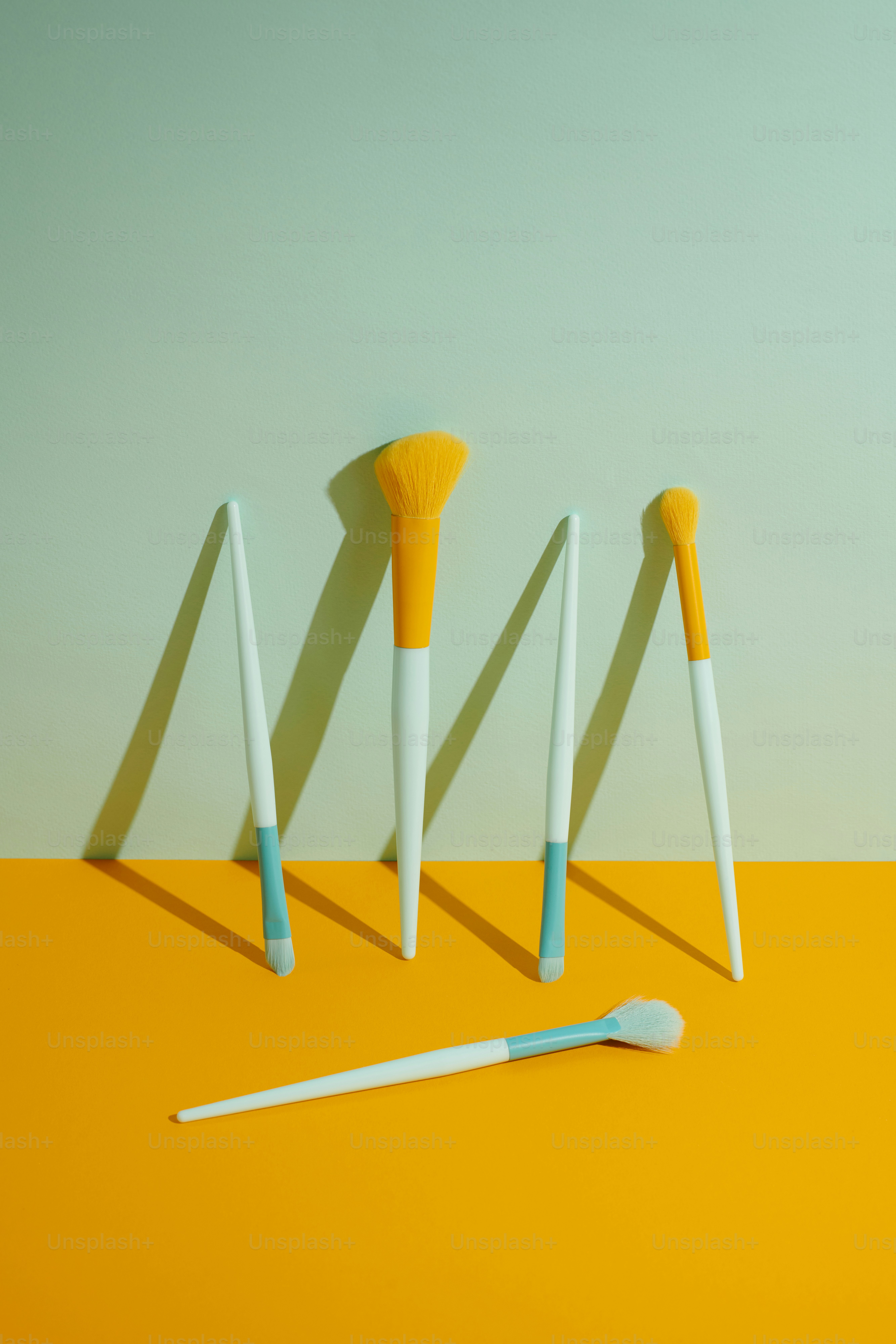 A group of three toothbrushes sitting on top of a yellow table photo ...