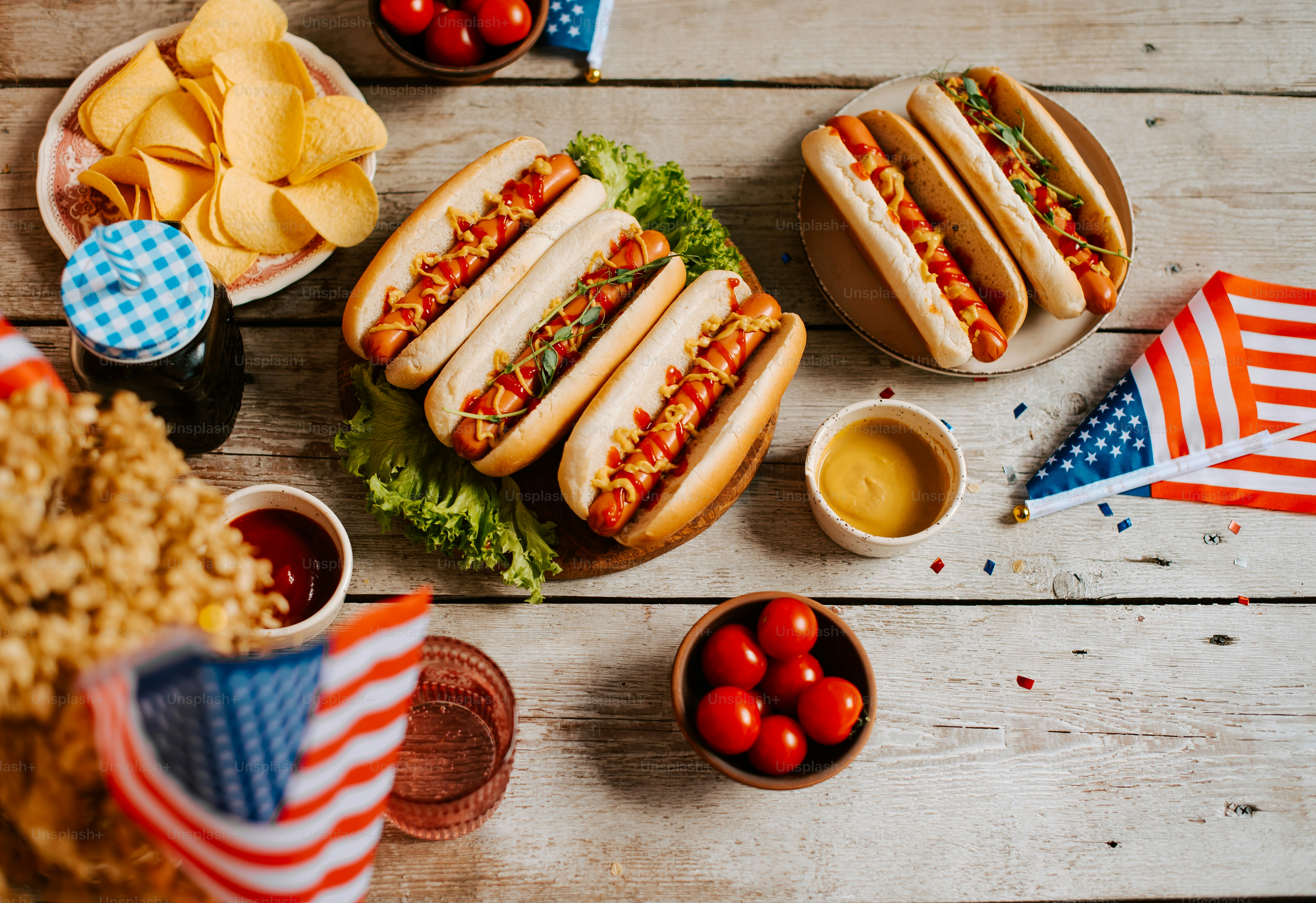 A table topped with plates of hot dogs and chips photo – Party food ...