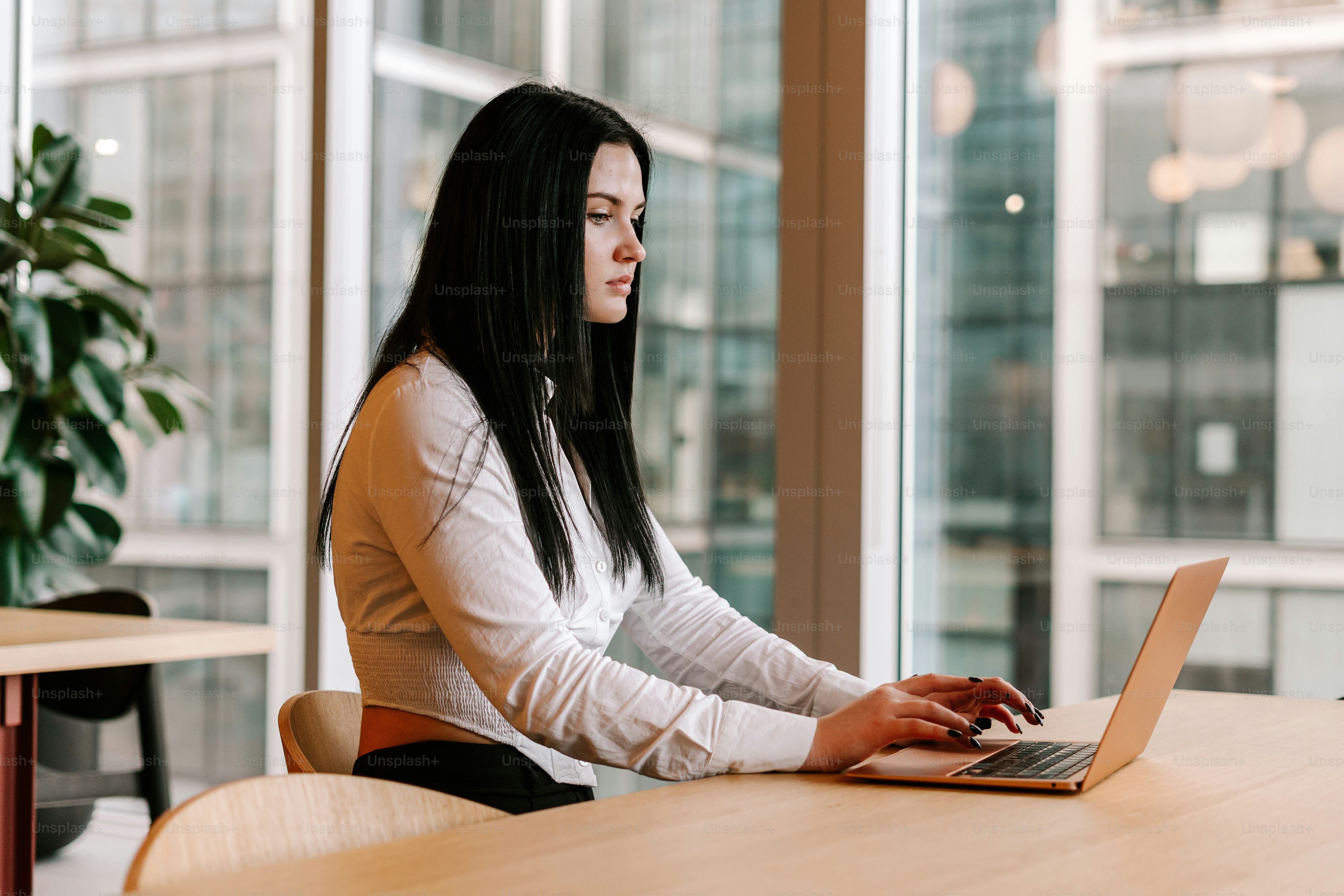 A woman sitting at a table using a laptop computer photo – Workspace ...